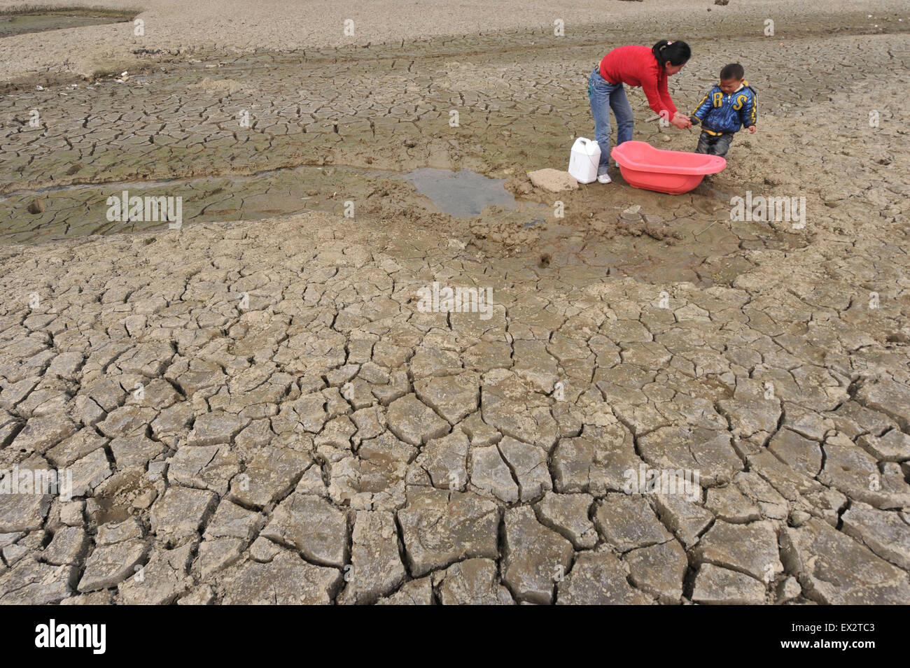 A boy carries a container as he stands on a partially dried-up ...