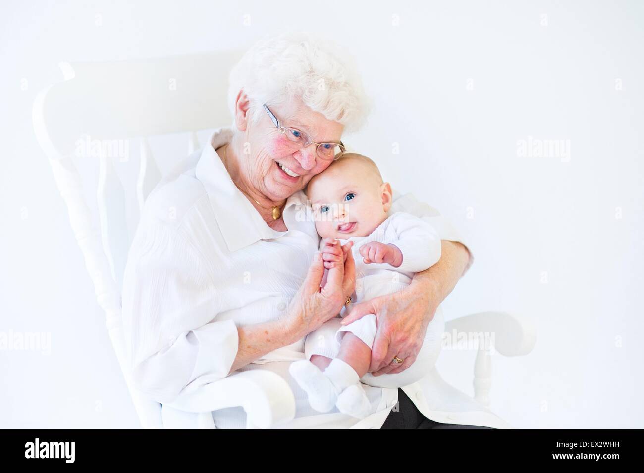 Beautiful grandmother singing to her newborn baby grandson sitting in a ...