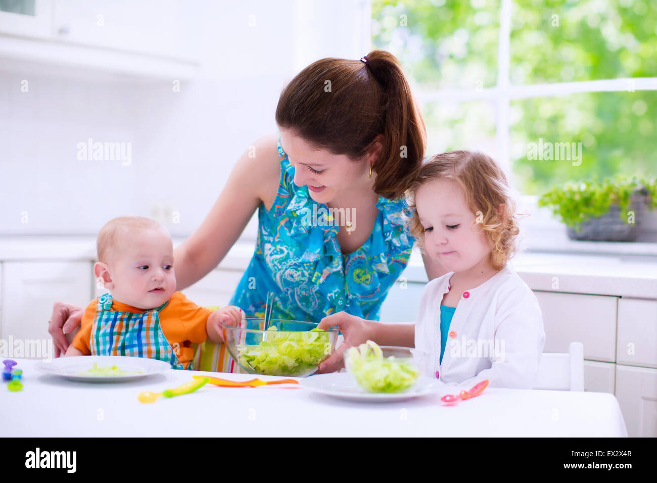 Young mother and two children cooking in a kitchen. Parent and kids ...