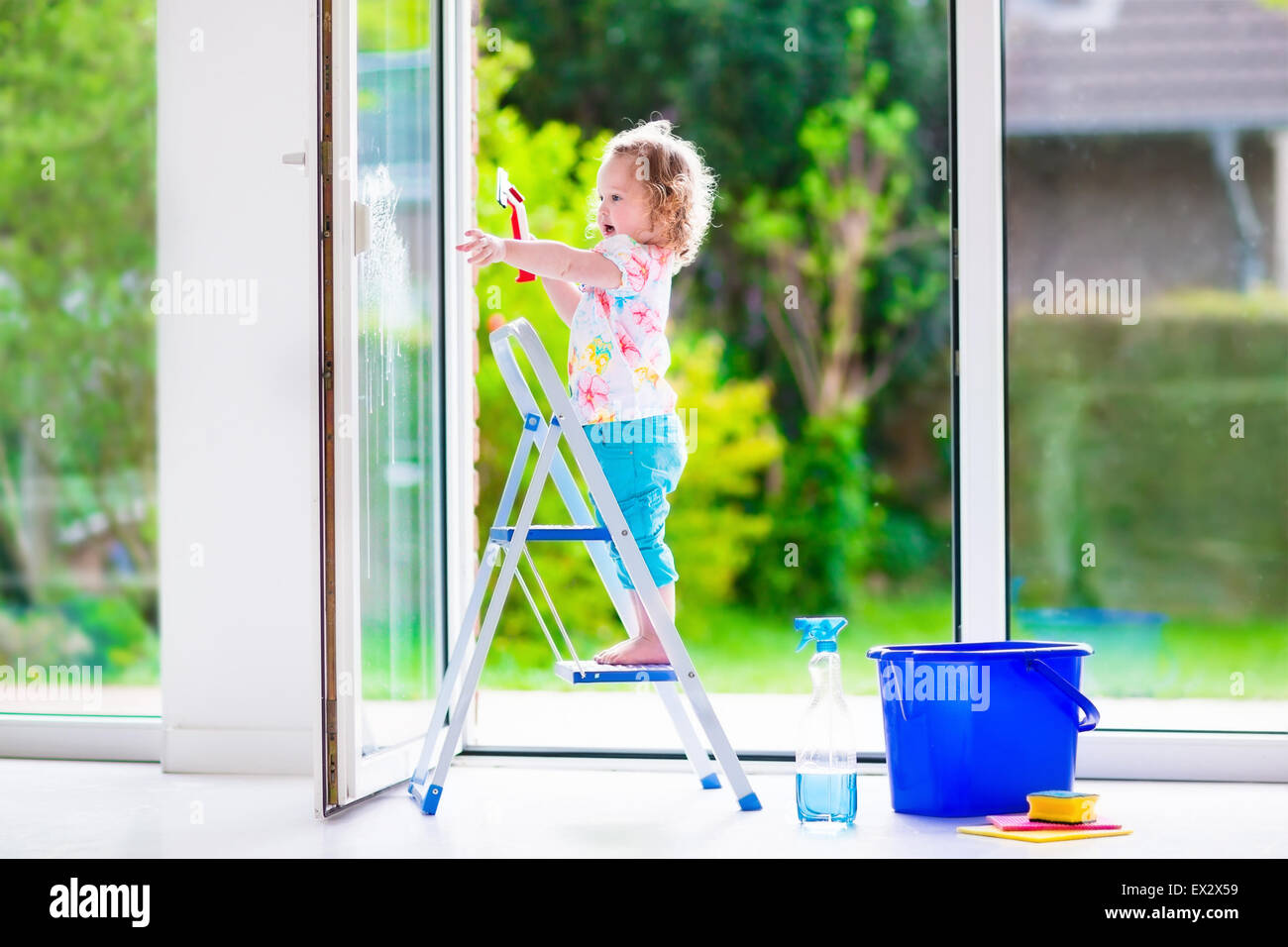 Little girl washing a window. Kids clean the house. Children help at ...
