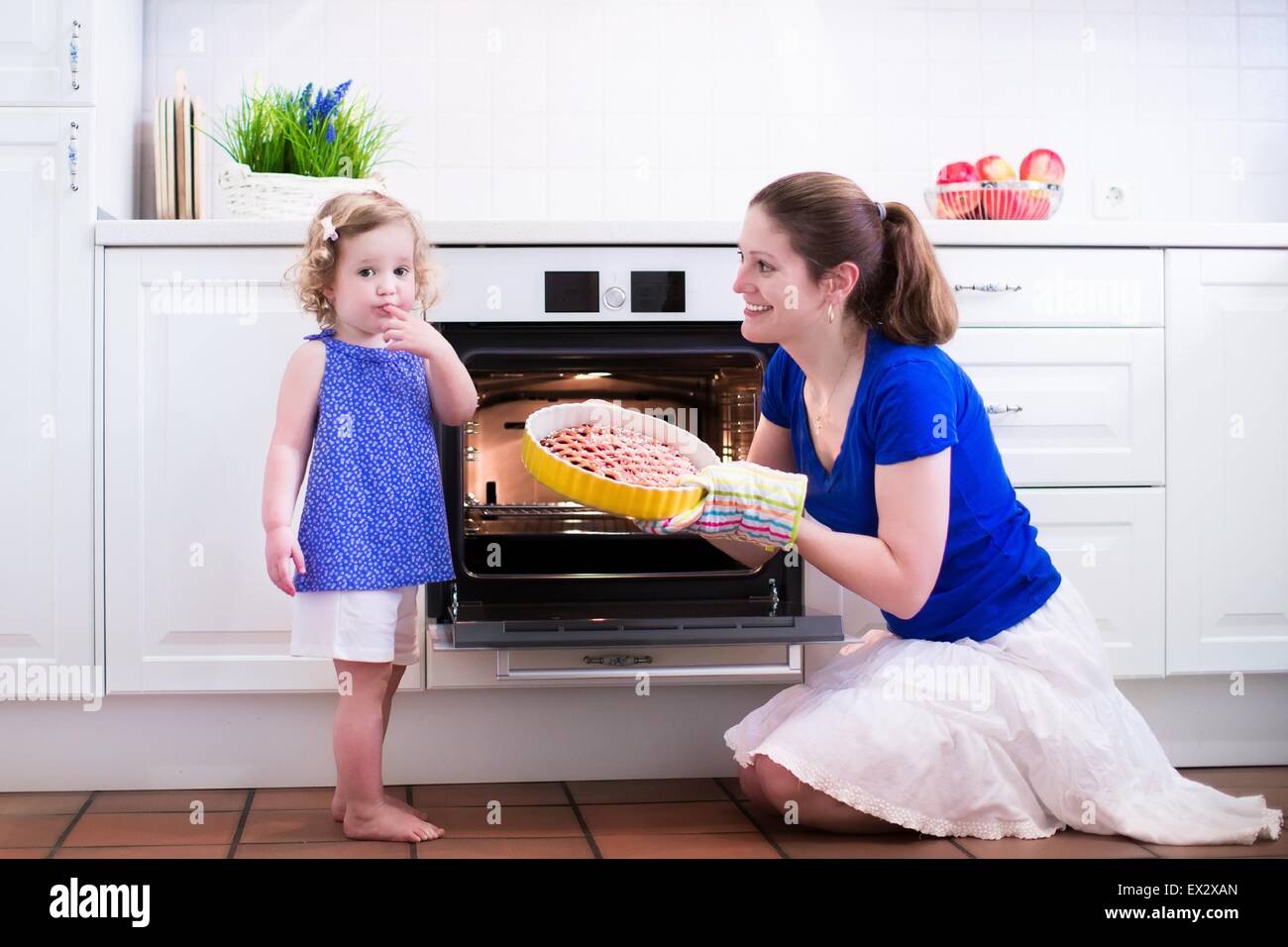 Mother and child bake a pie. Young woman and her daughter cook in a ...