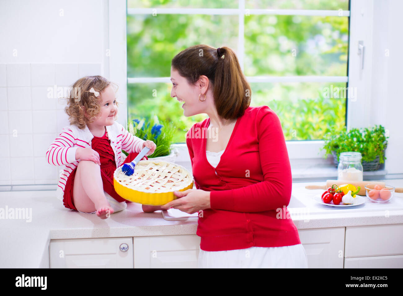 Mother and child bake a pie. Young woman and her daughter cook in a ...