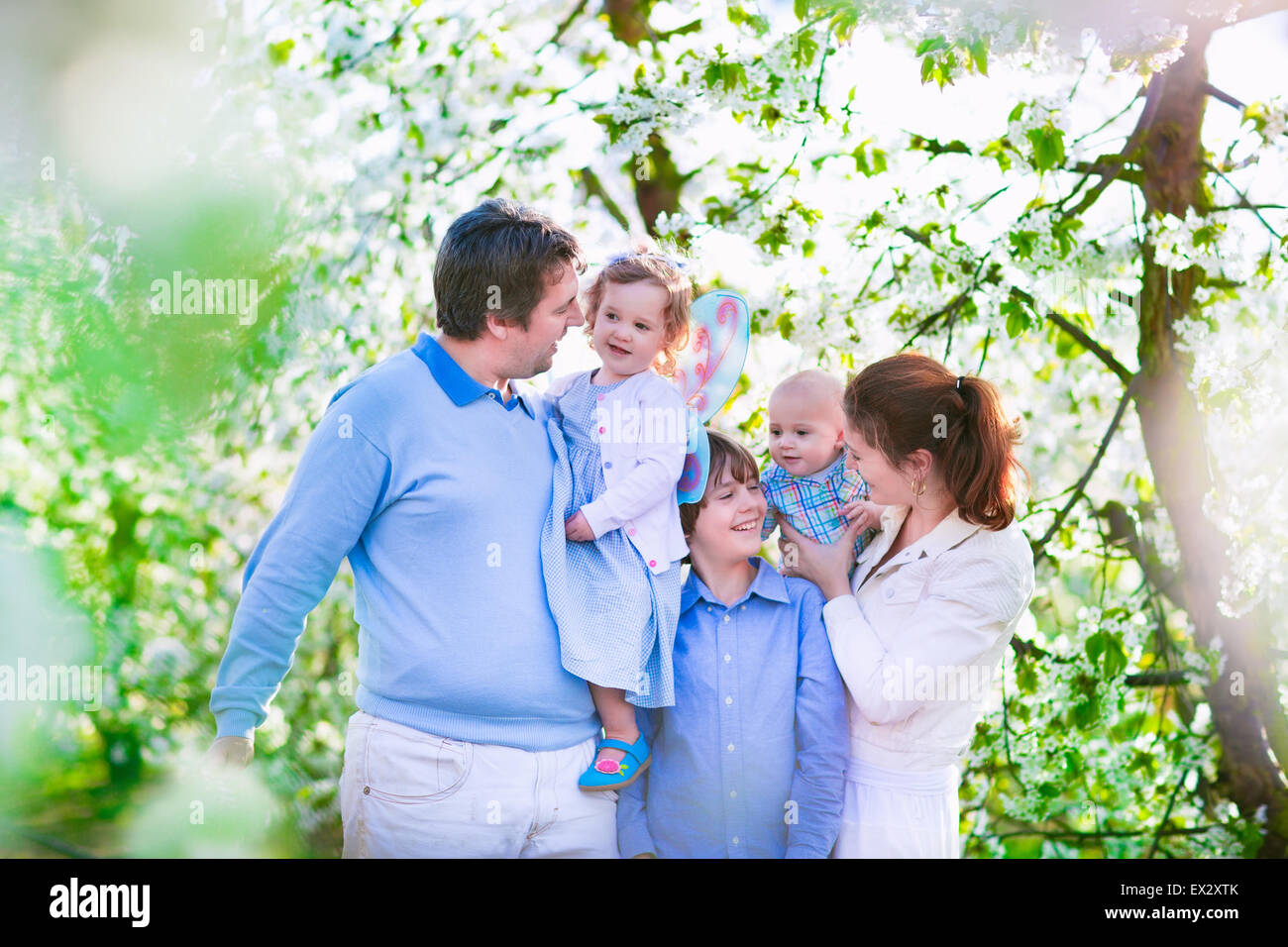 Family with kids in a blooming spring garden. Parents with three ...