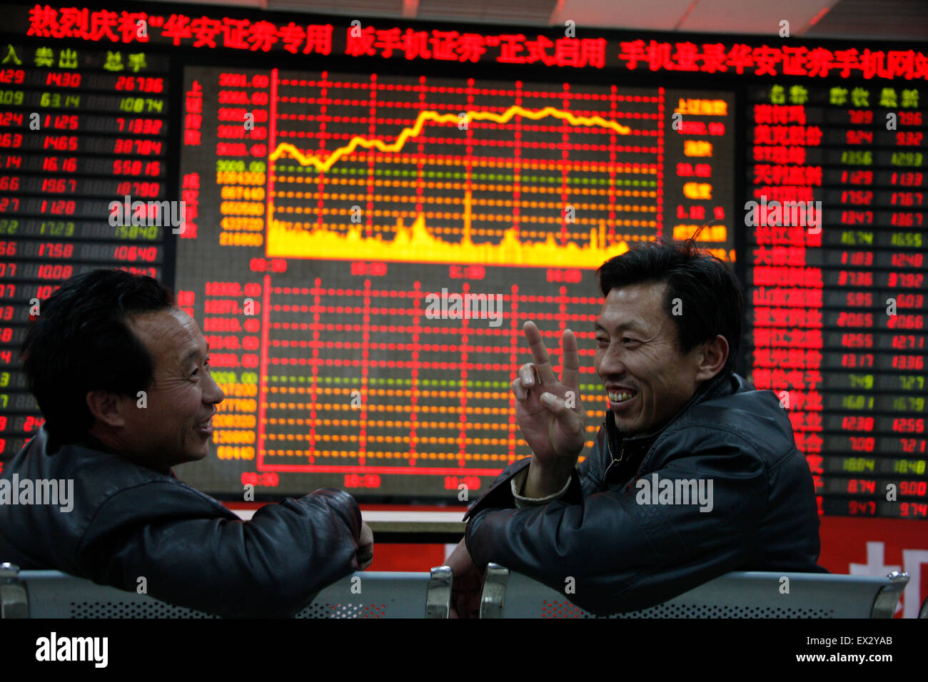 Investors chat in front of an electronic board with stock information ...