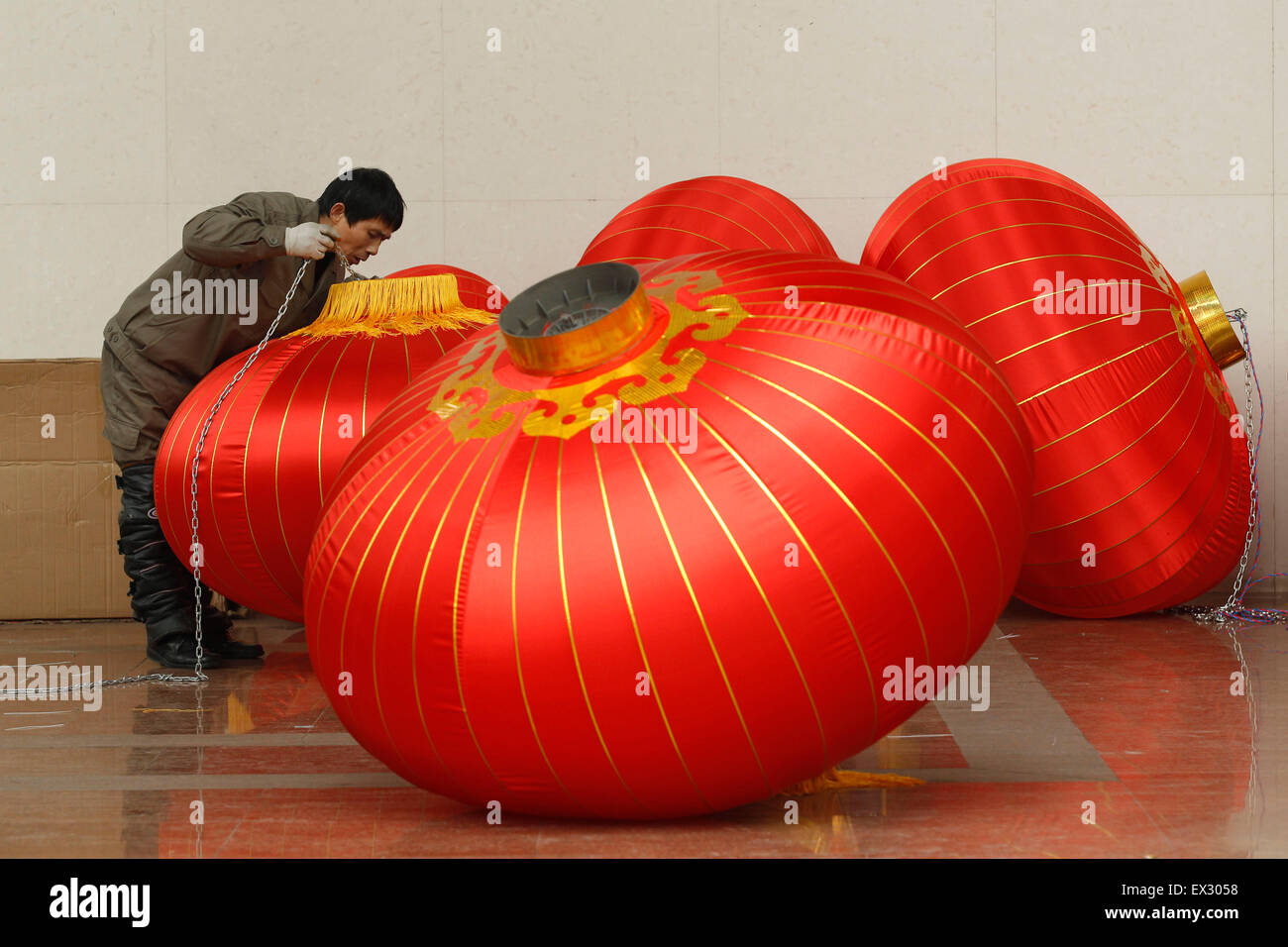 A labourer hangs lantern to celebrate the Lantern Festival on a street ...
