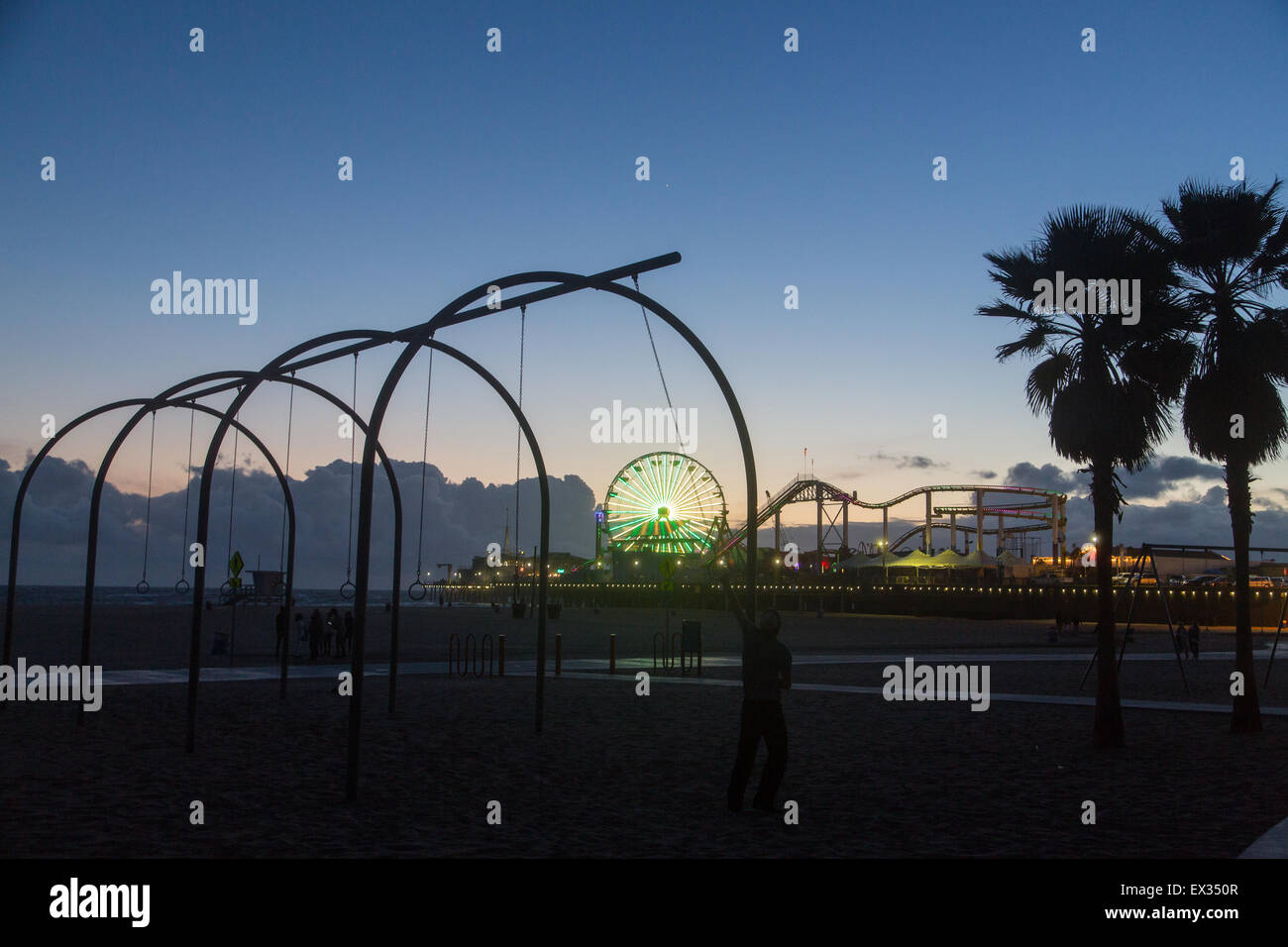 Storm clouds hover behind the Santa Monica Pier as a man exercises on ...