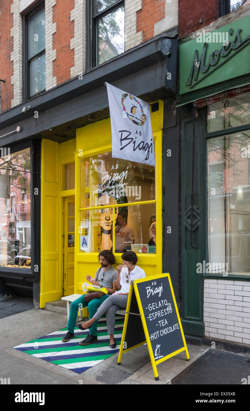 A young couple eating on a bench outside A.B. Biagi gelato, sorbet and ...