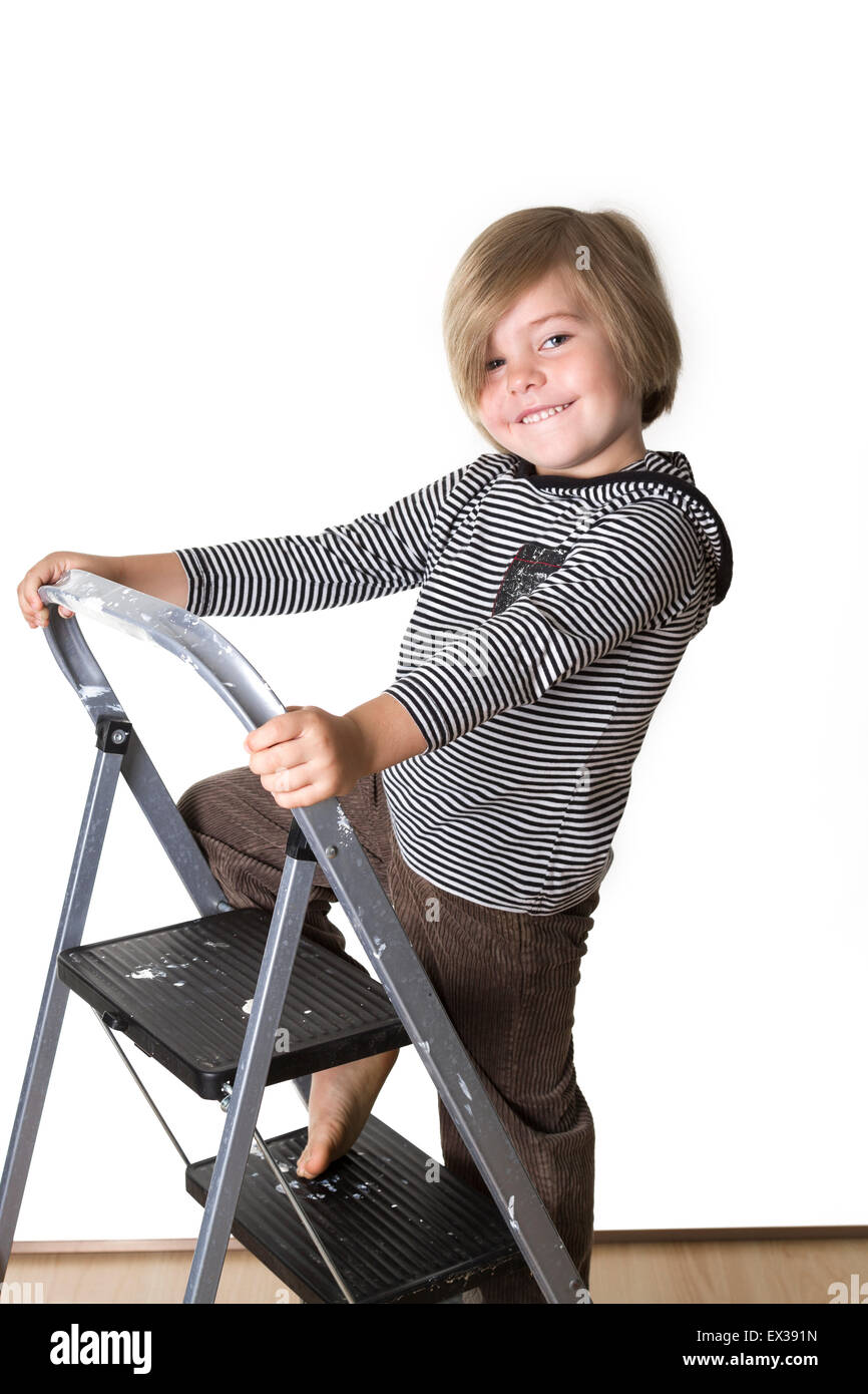 Young boy wearing striped shirt and hood, standing on a ladder, smiling ...
