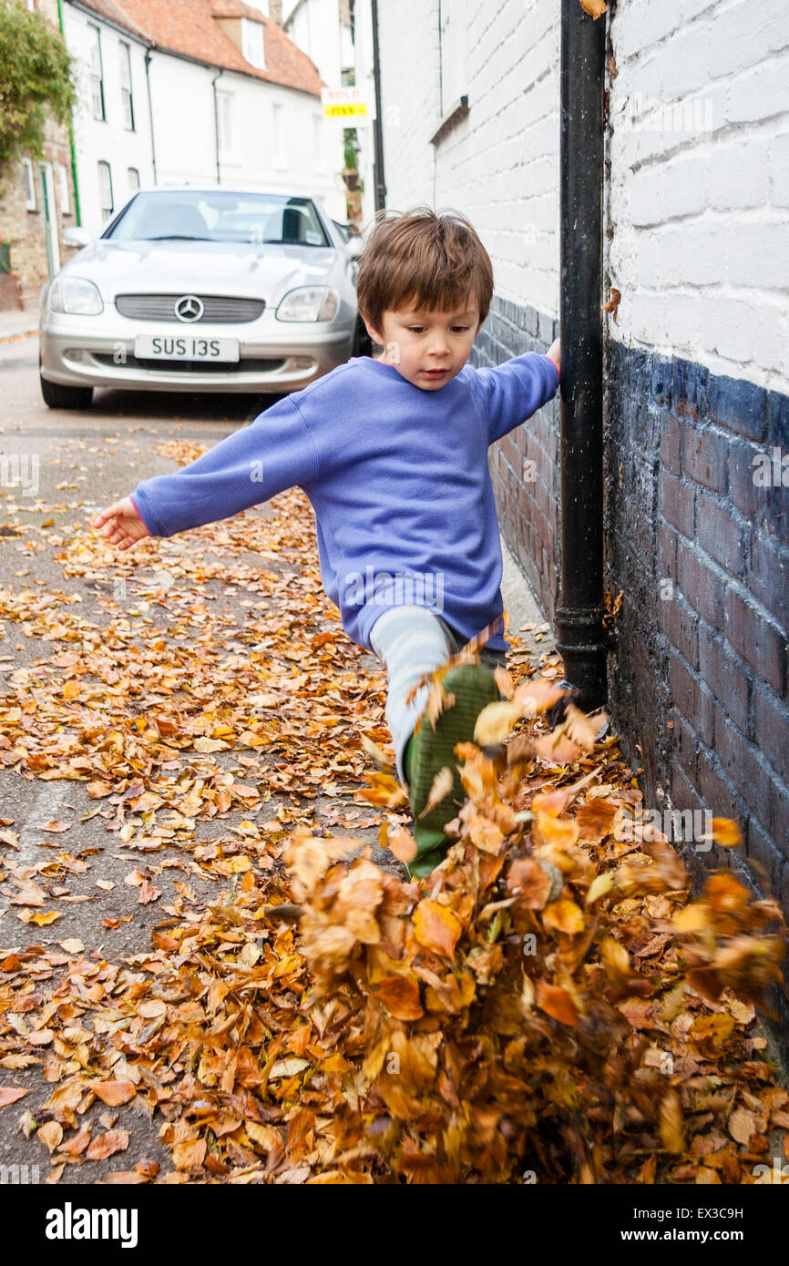 Caucasian child, boy, 5-6 year old, walking along street covered in ...