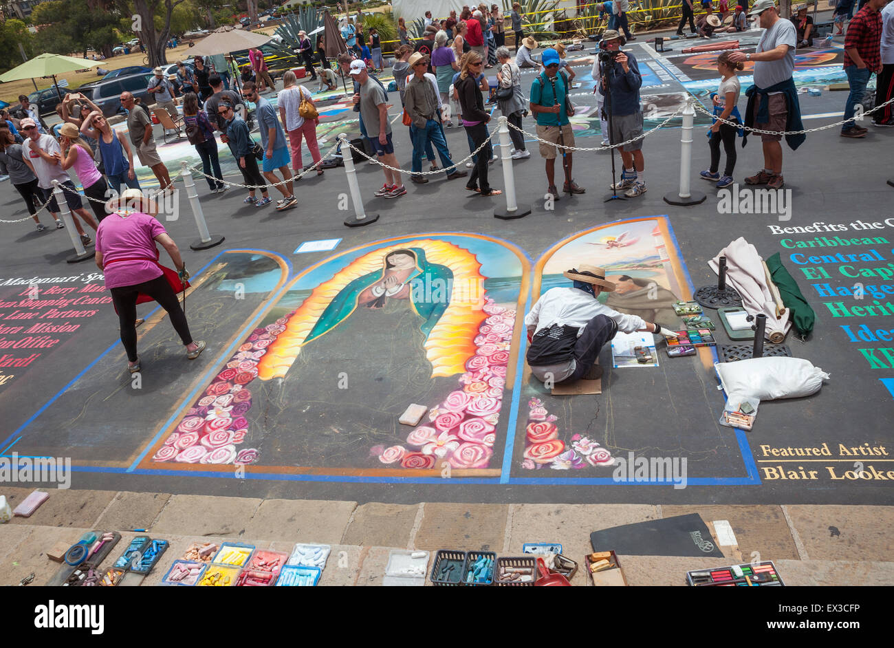 A crowd is watching artists painting with chalk at the annual ...