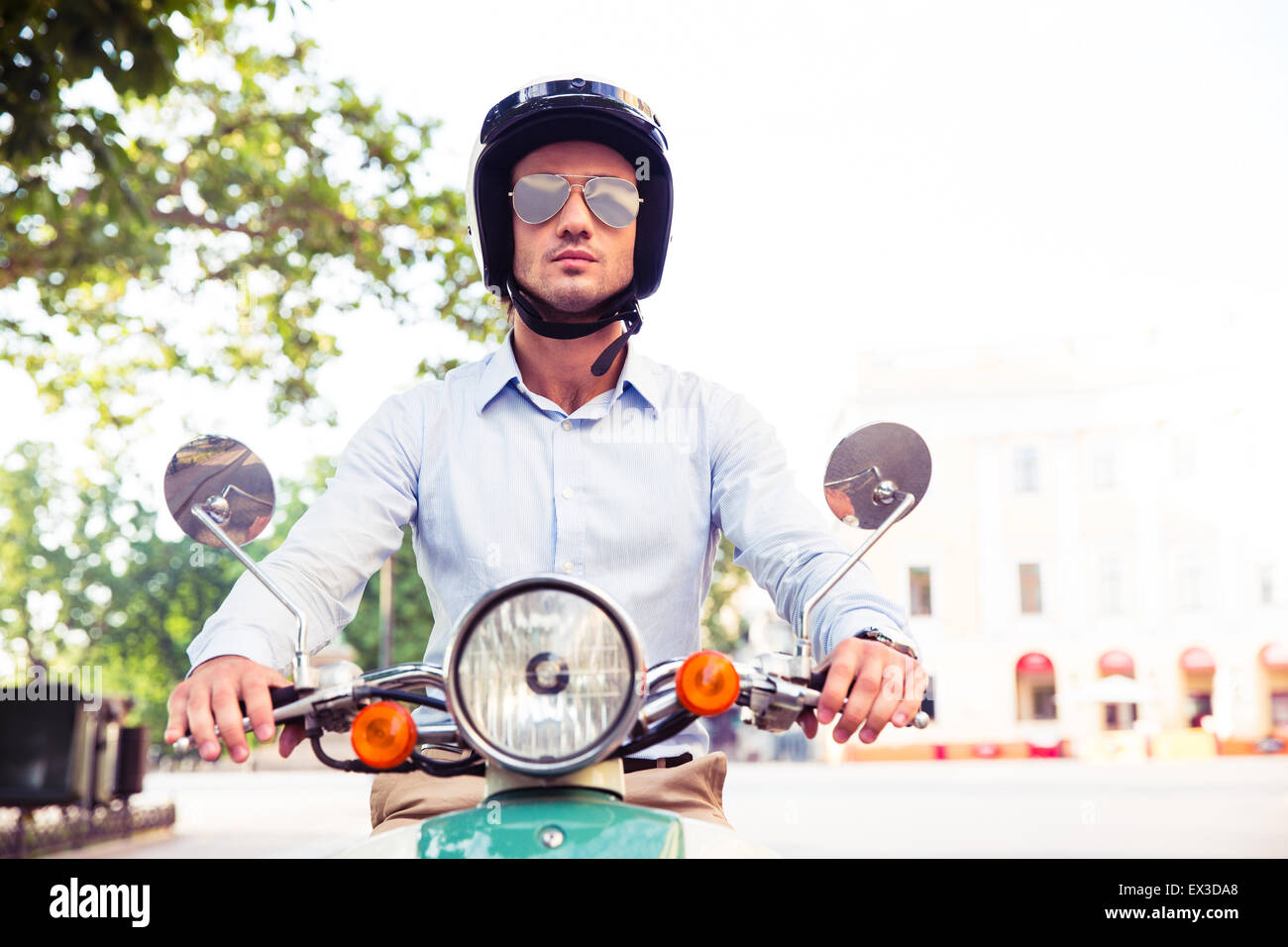 Handsome man in helmet riding on scooter in town Stock Photo - Alamy