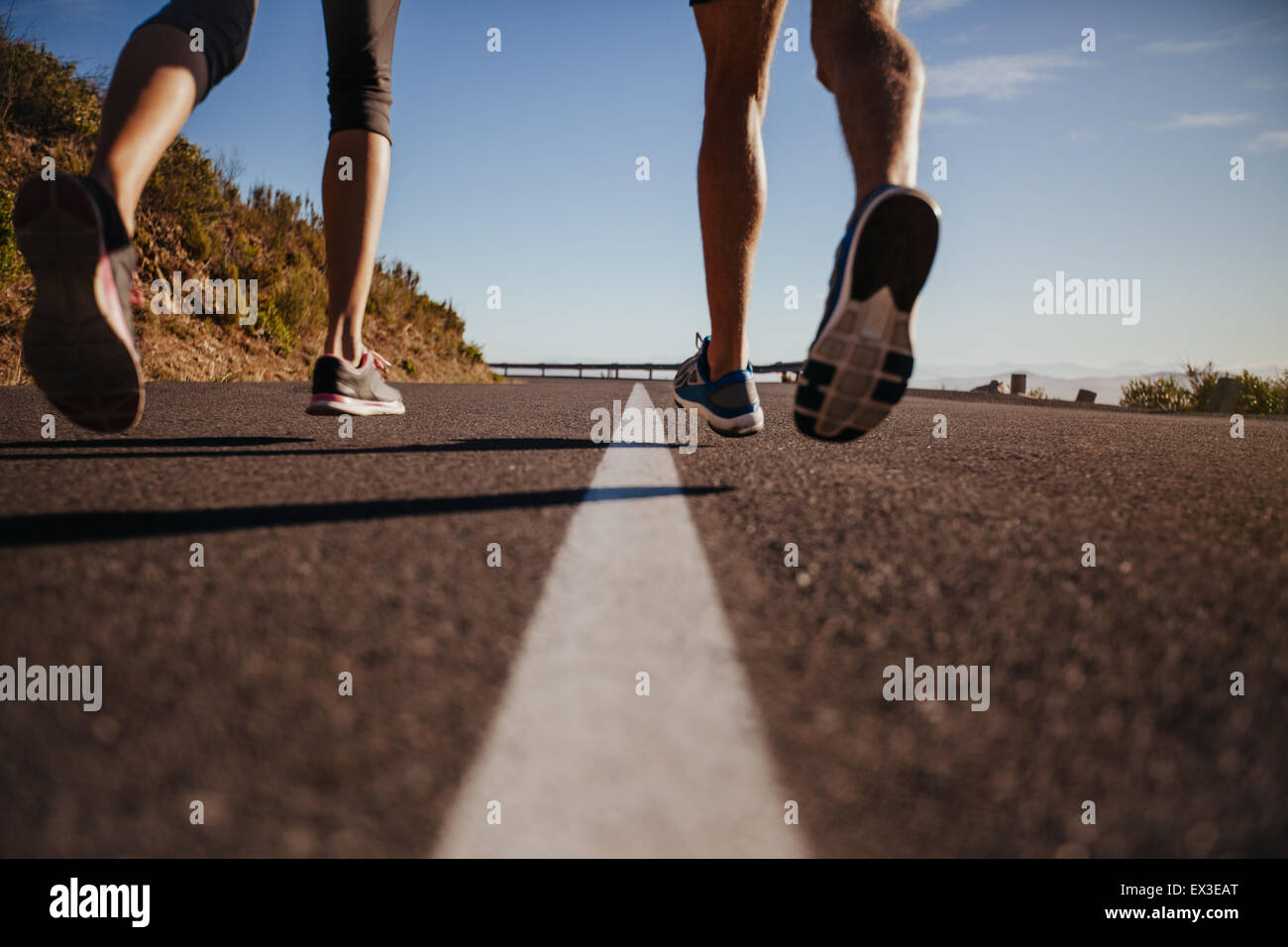 Cropped shot of runners running on the road. Rear view close-up image ...