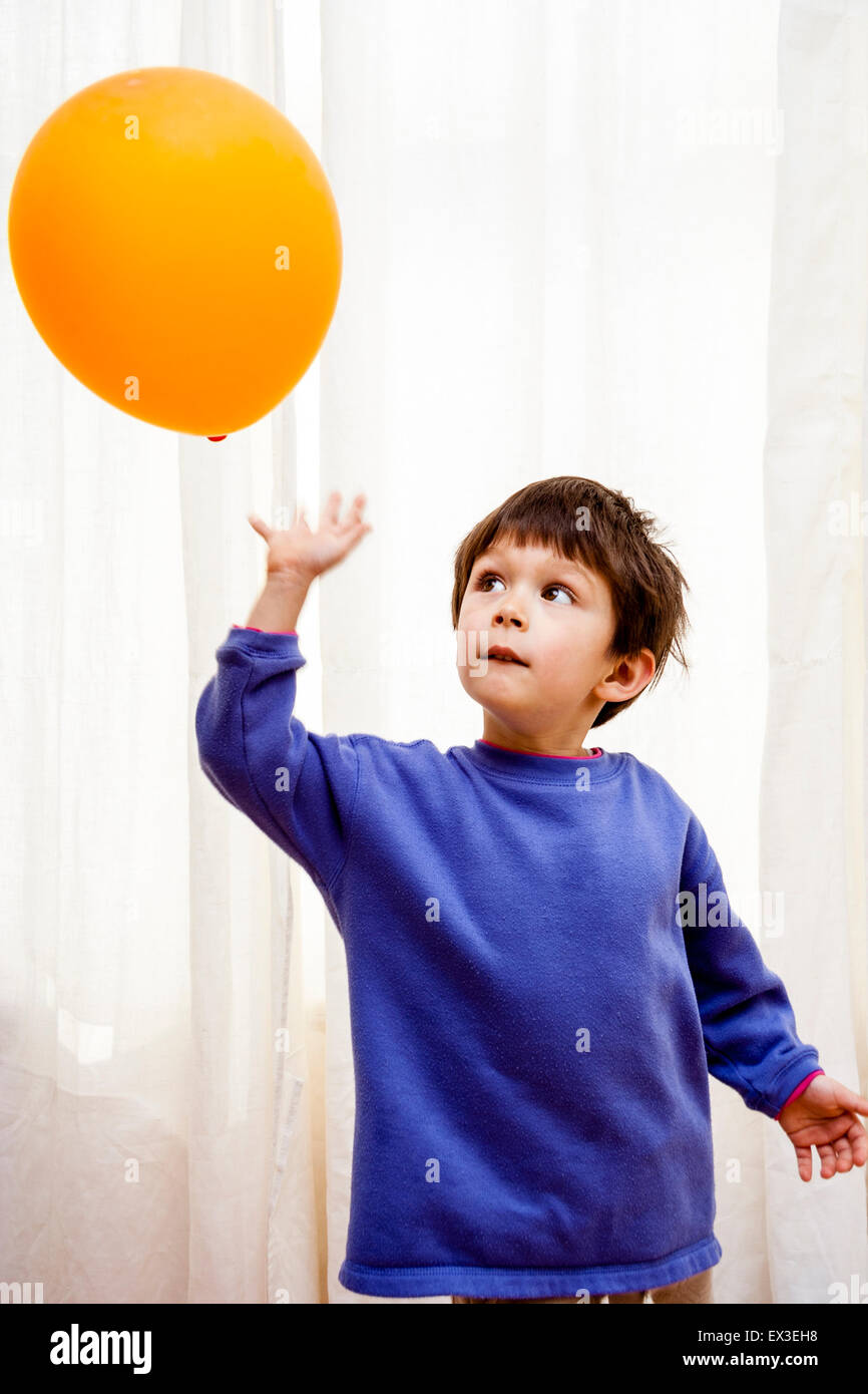 Caucasian child, boy, playing indoors with colored balloons. 6-7 year ...