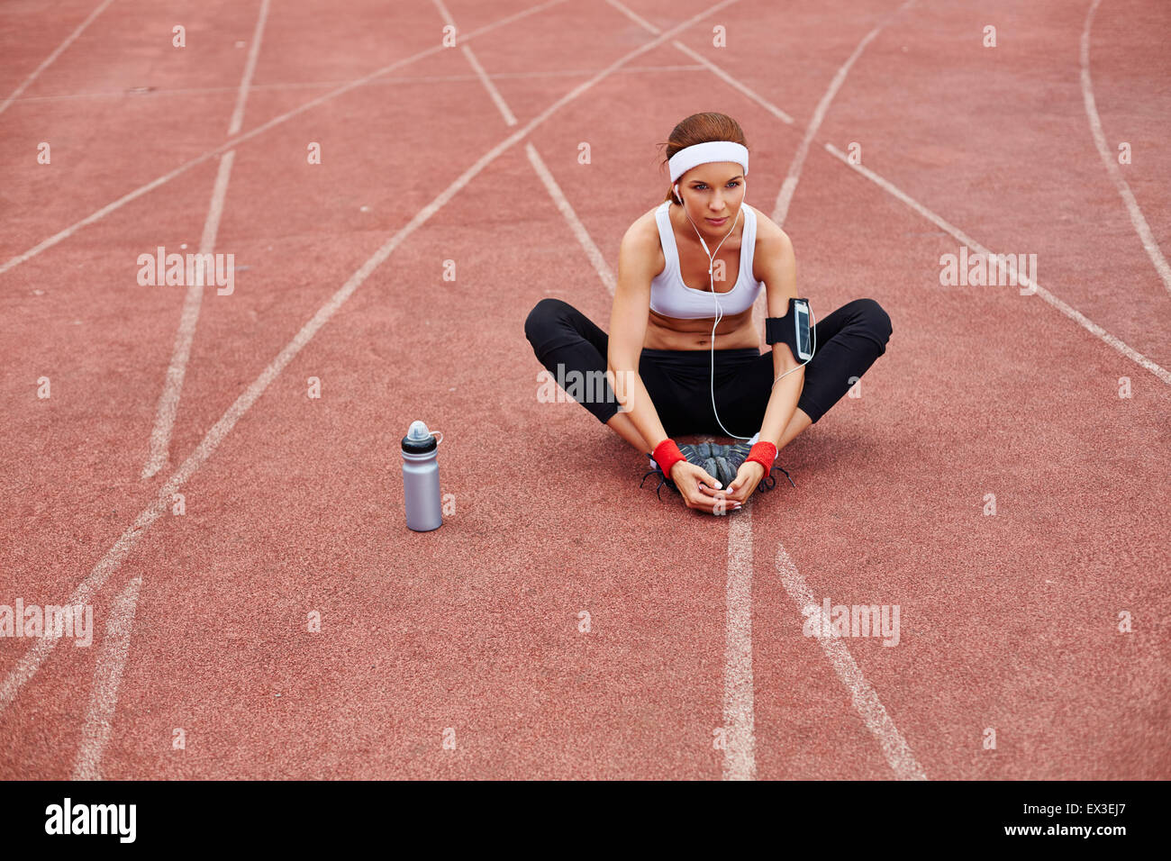 Fit woman in activewear sitting on racetrack Stock Photo - Alamy