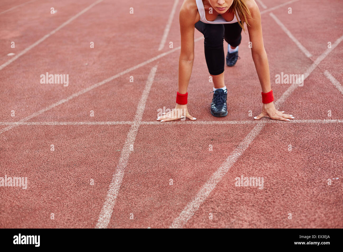Sporty female on racetrack ready to run Stock Photo - Alamy