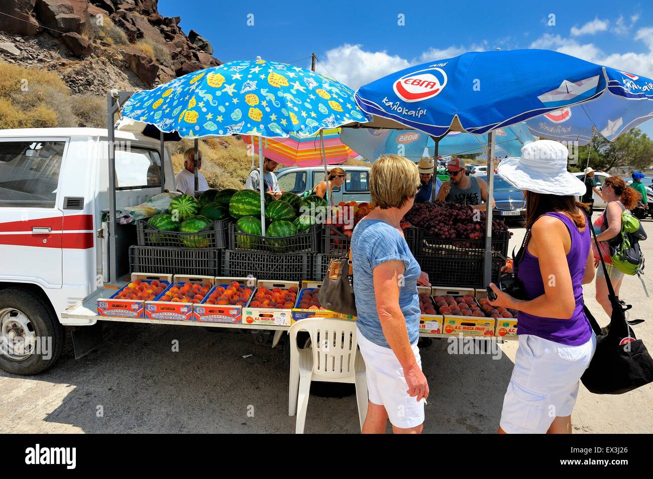 Tourists looking at a lorry selling fresh fruit in Santorini Greece ...