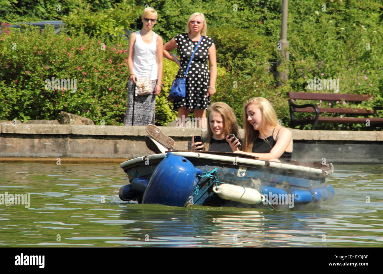 Teenage girls look at their mobile phones during a ride on a boating ...