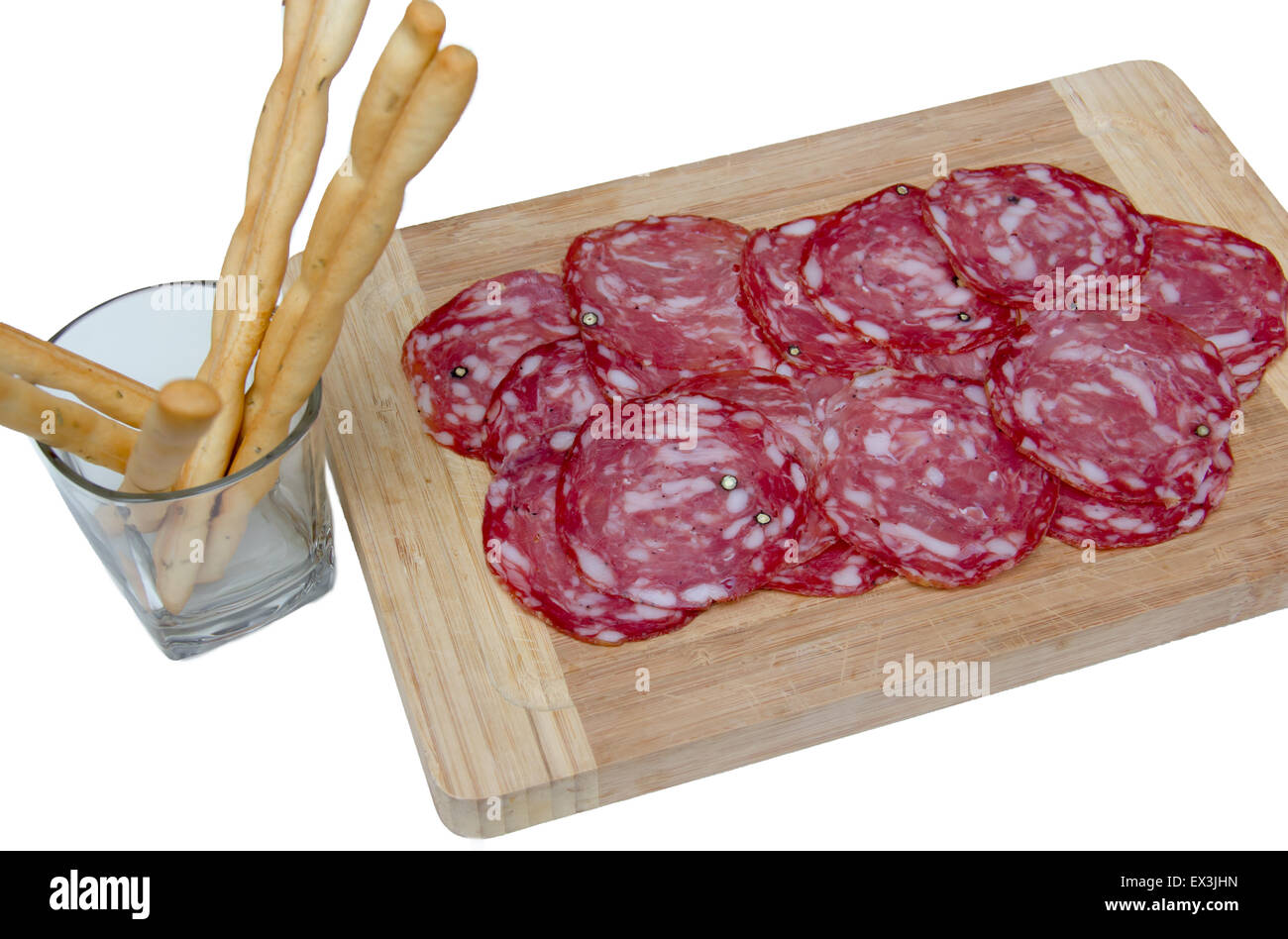 Slices of salami on cutting board and bread sticks on white background ...