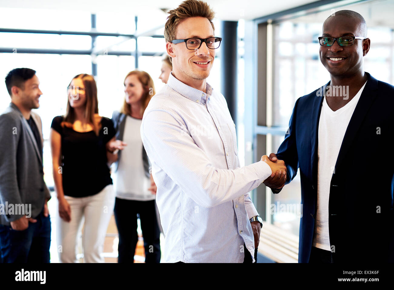 Black male executive and white male executive shaking hands looking at ...