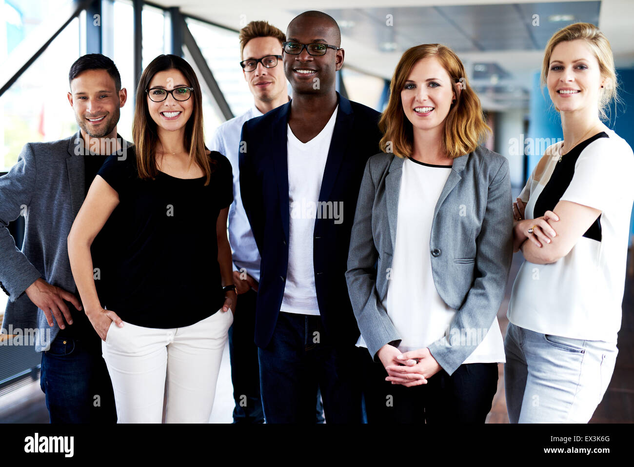 Group of young executives standing, smiling at camera and posing for ...
