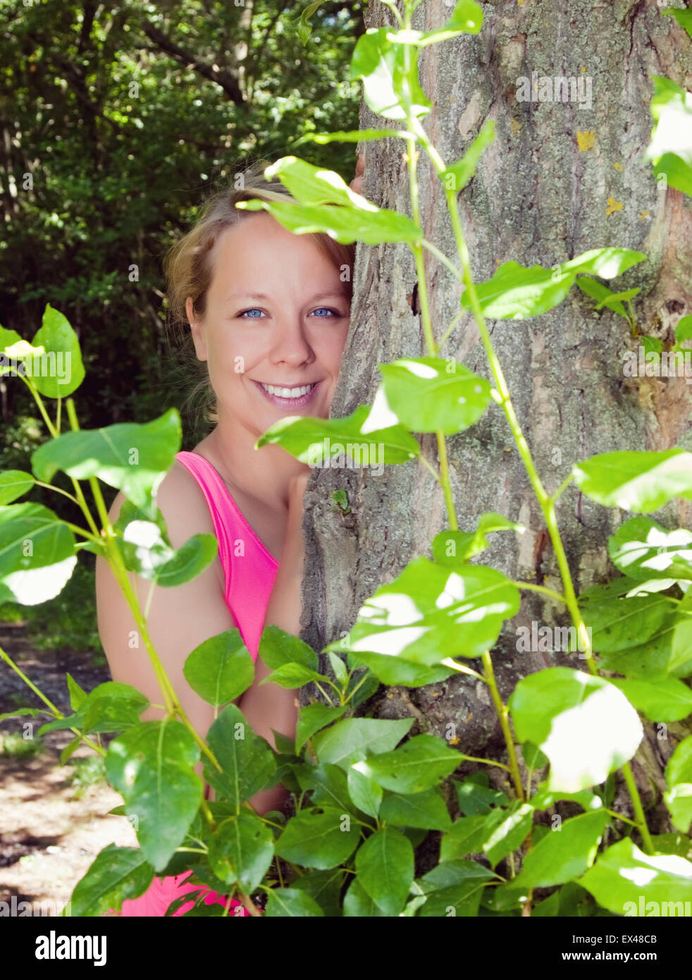 pretty woman hidden behind a tree Stock Photo - Alamy
