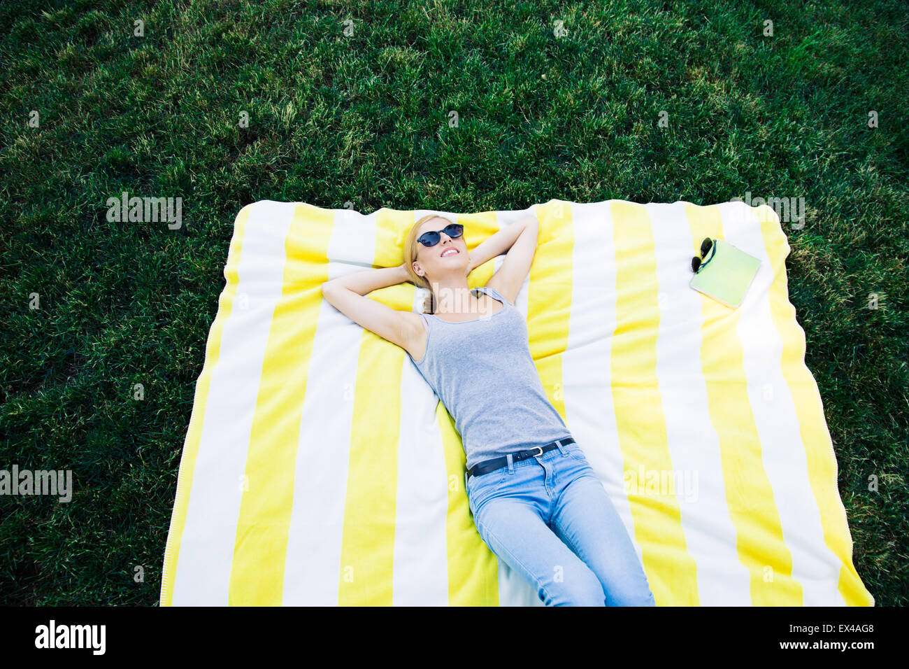 Smiling young woman lying on the mat in park Stock Photo - Alamy