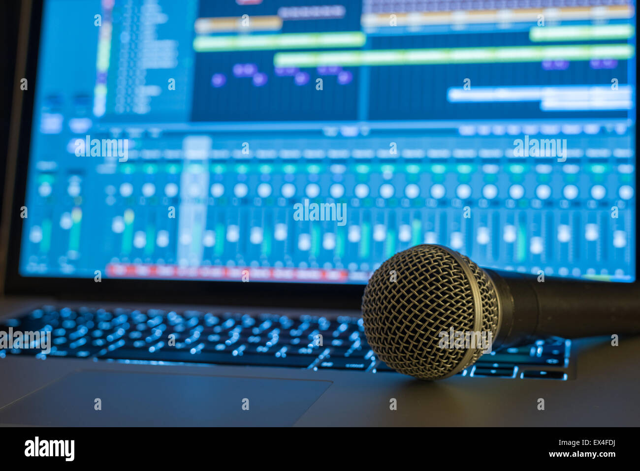 Microphone laying on laptop with digital audio workstation in ...