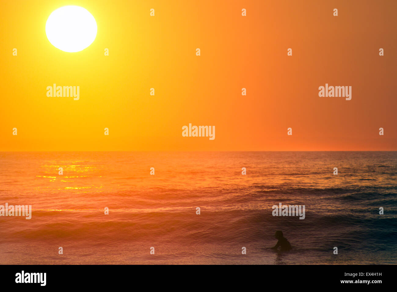 Surfer at sunset Stock Photo - Alamy