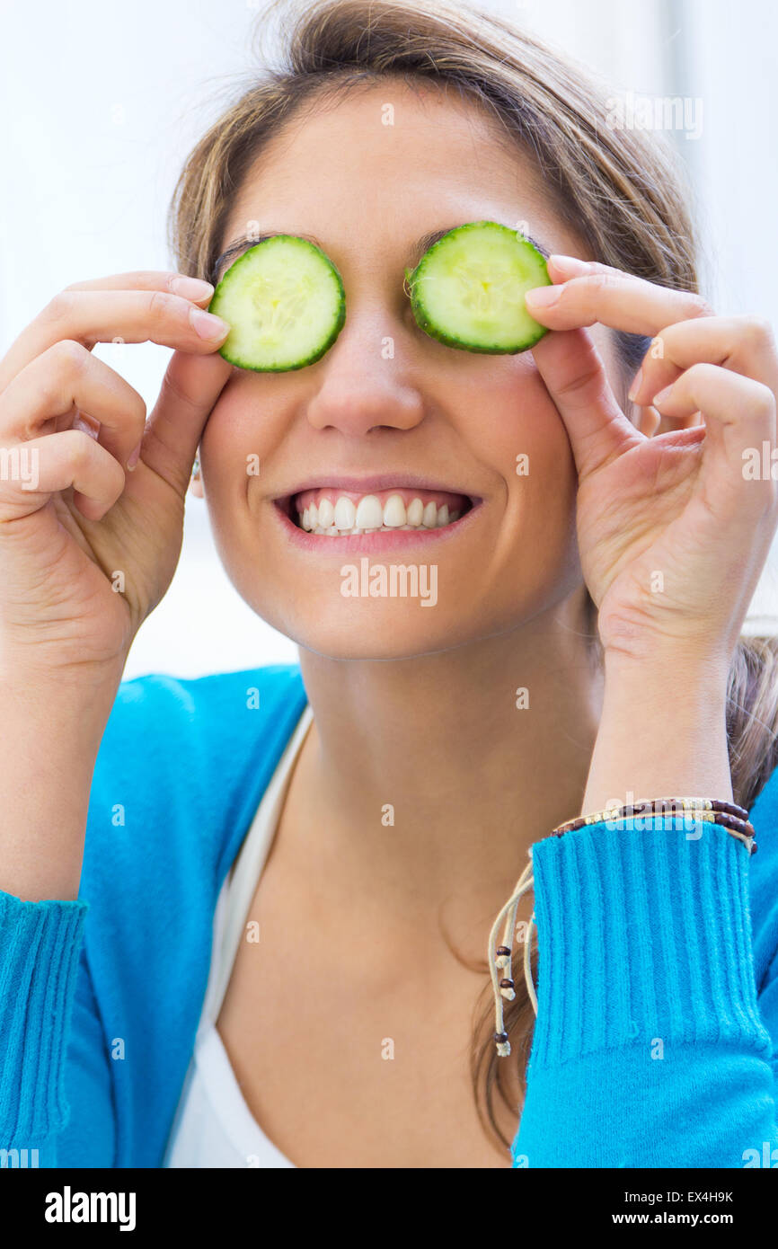 Portrait of pretty young woman having fun with a cucumber in the ...