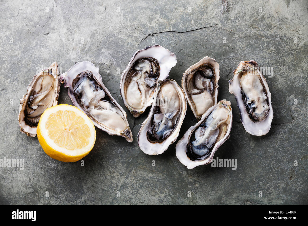 Opened Oysters on stone slate plate with lemon Stock Photo - Alamy