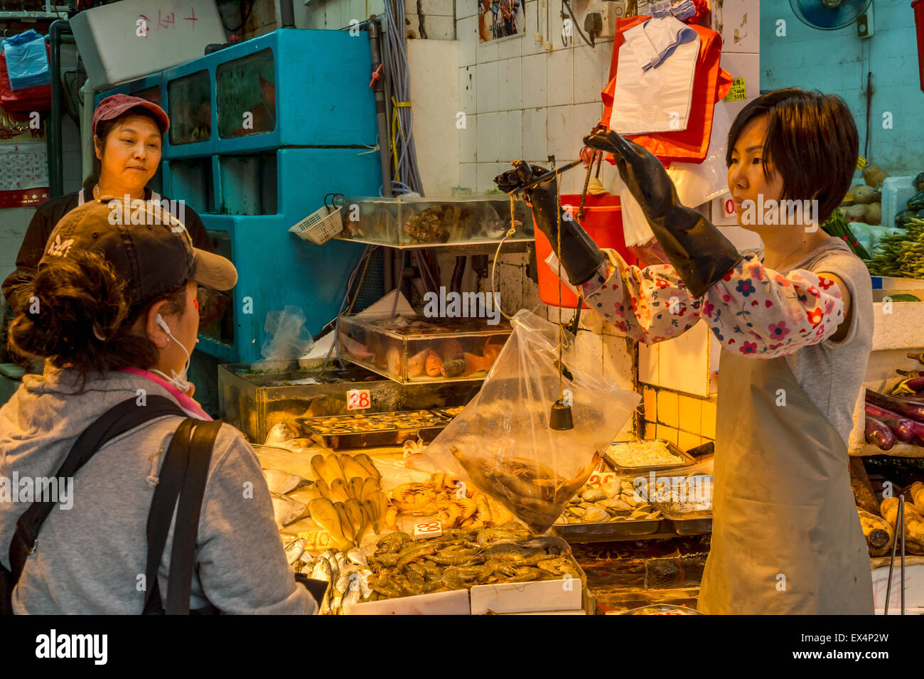 Seafood merchant weighs shrimps at the food market in Hong-Kong, China ...
