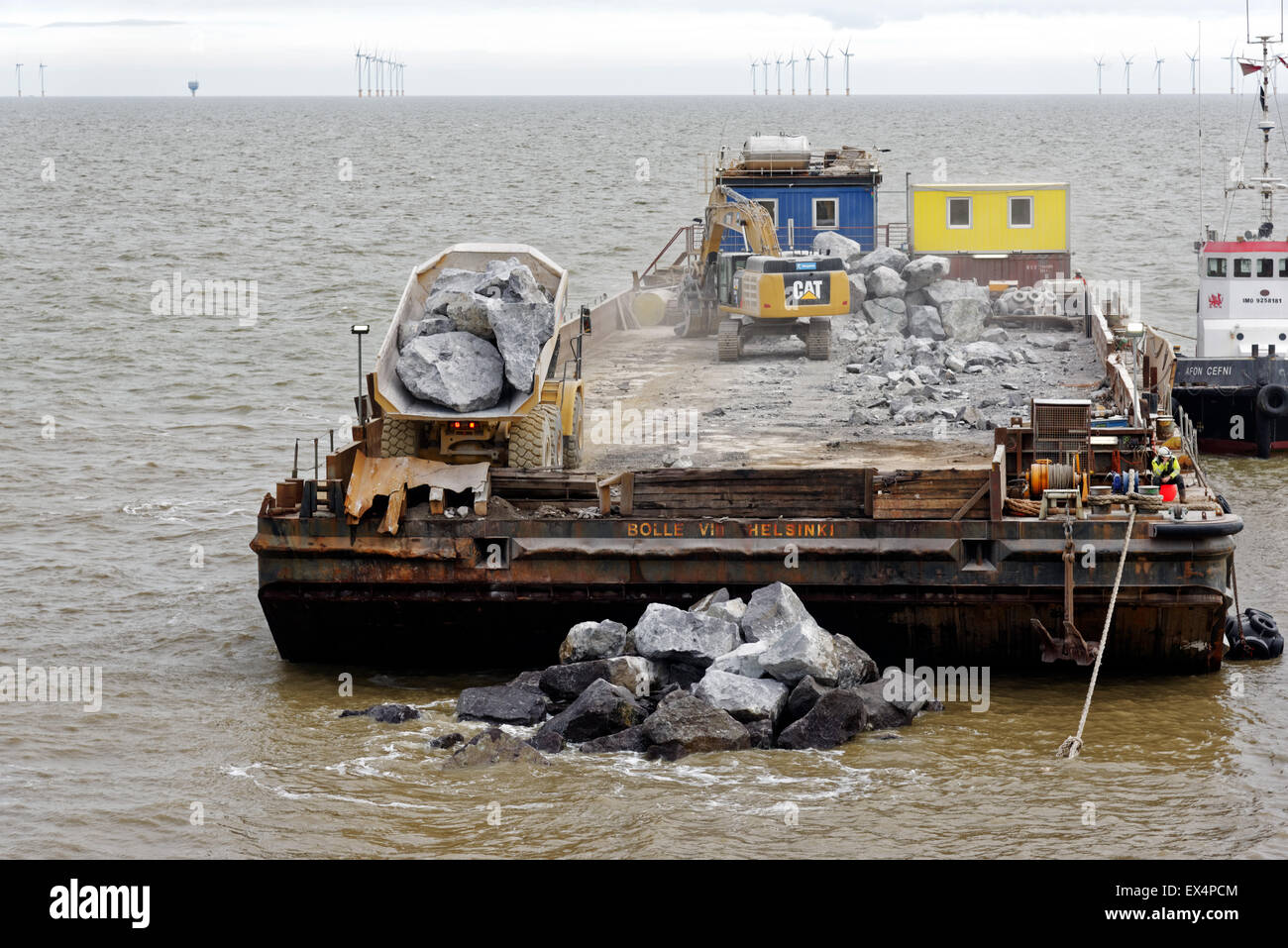 A barge being used to make sea defences - a lorry dumping huge boulders ...
