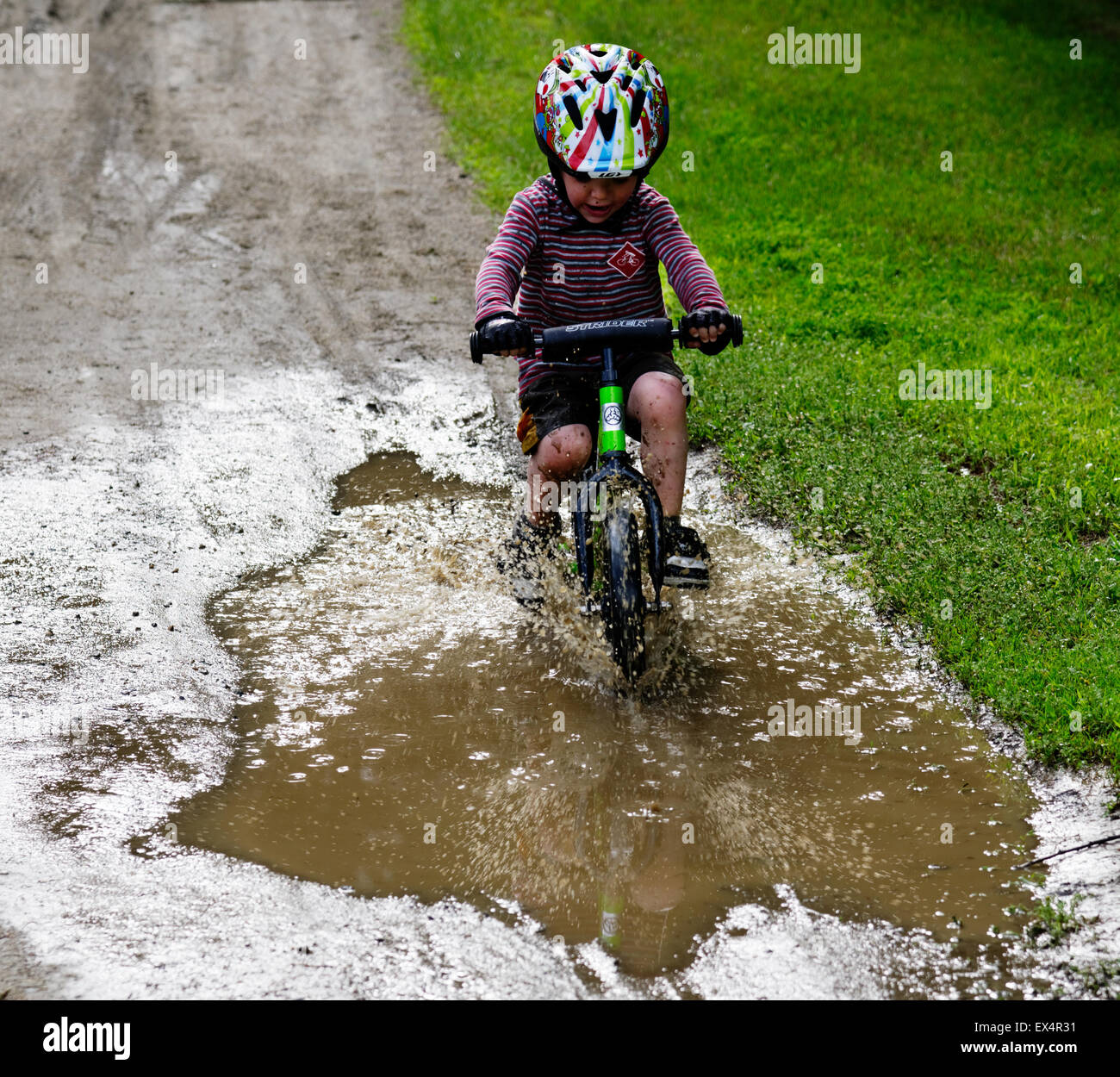 A young boy (3 yrs) riding a balance bike through a muddy puddle Stock ...