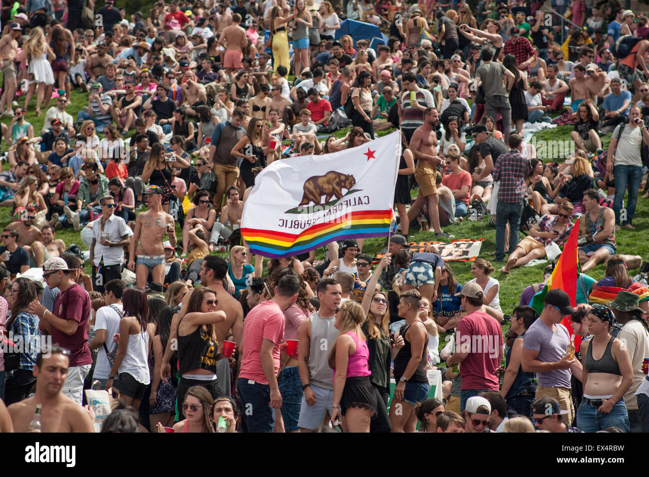A woman hoists a California State flag with rainbow colors through the ...