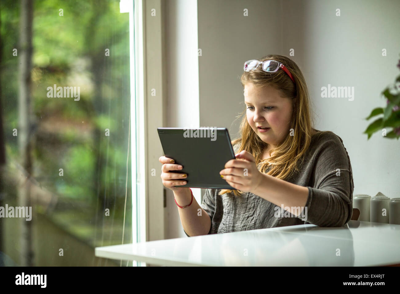 Teenage girl sitting with a tablet near the window in house Stock Photo ...