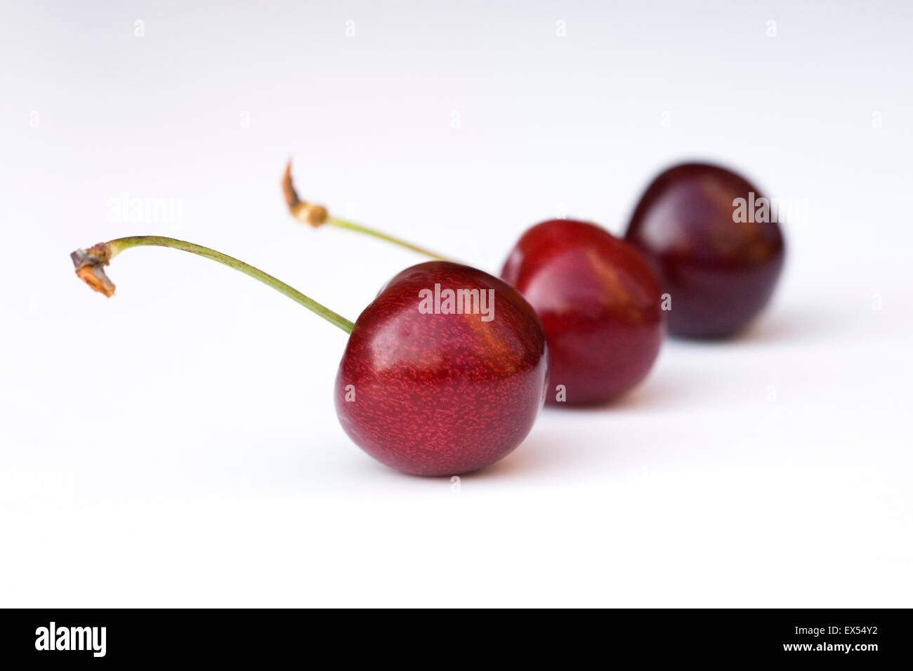 Three cherries on a white background Stock Photo - Alamy
