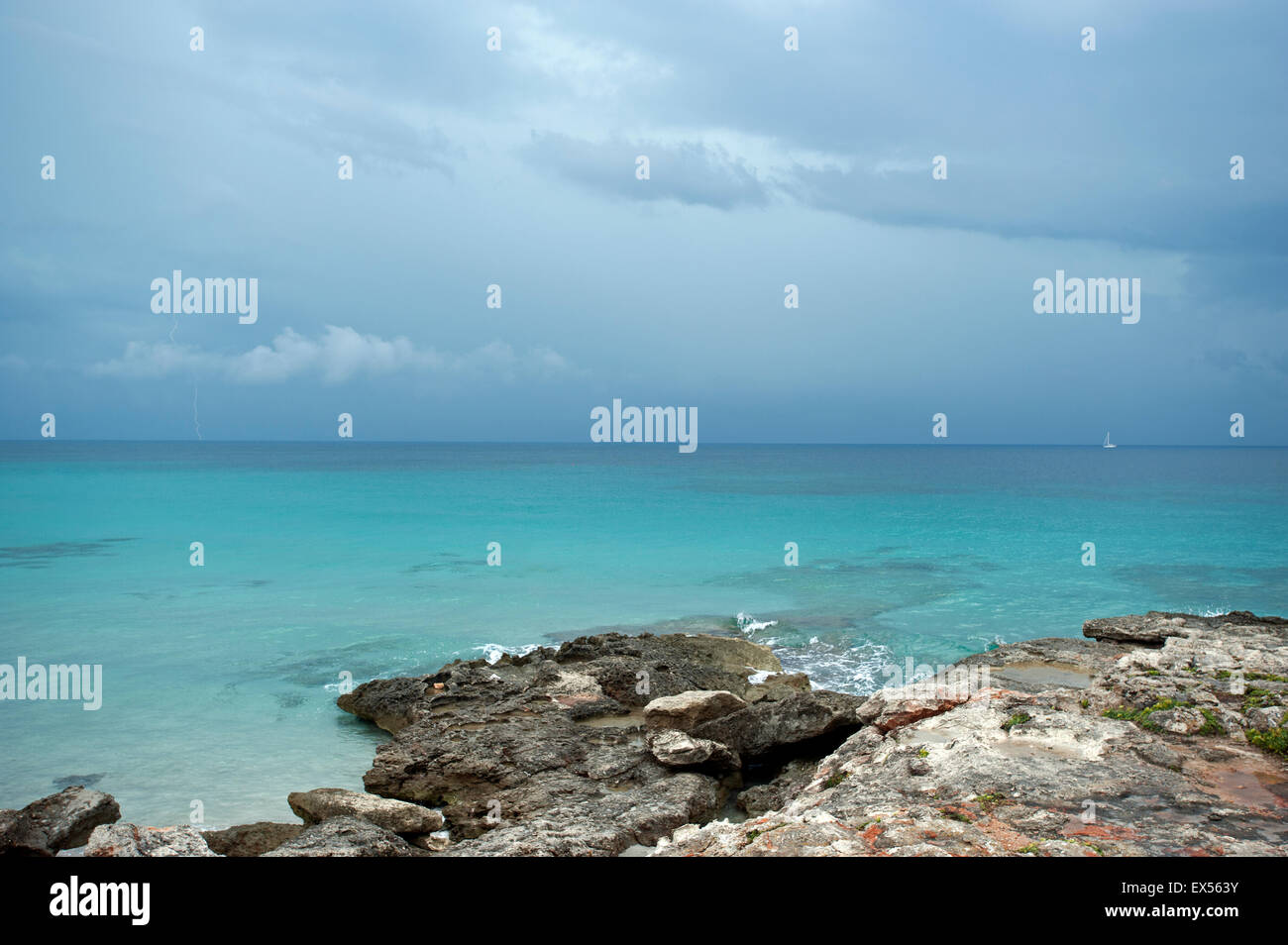 A lone yacht sails across in a rain storm the bay at Sant Tomas on the ...