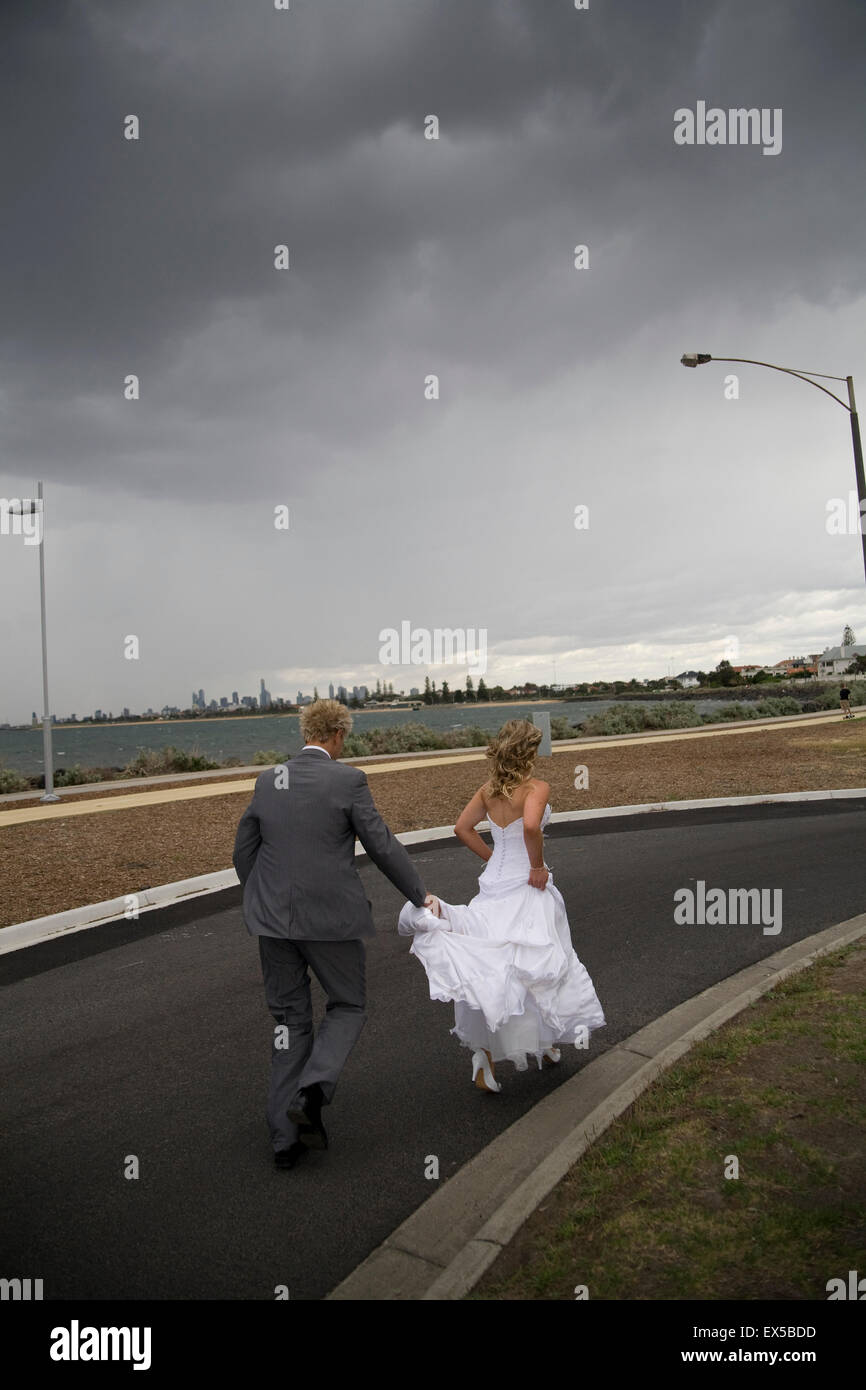 Bride and groom walking away with the groom holding her dress Stock ...