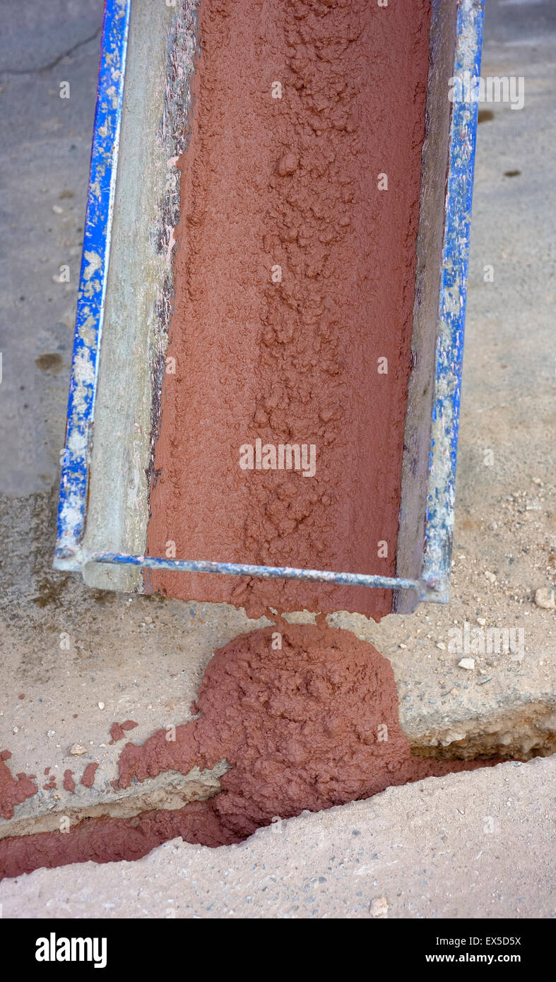 Pouring concrete colored red for filling fiber optic cables microtrench ...