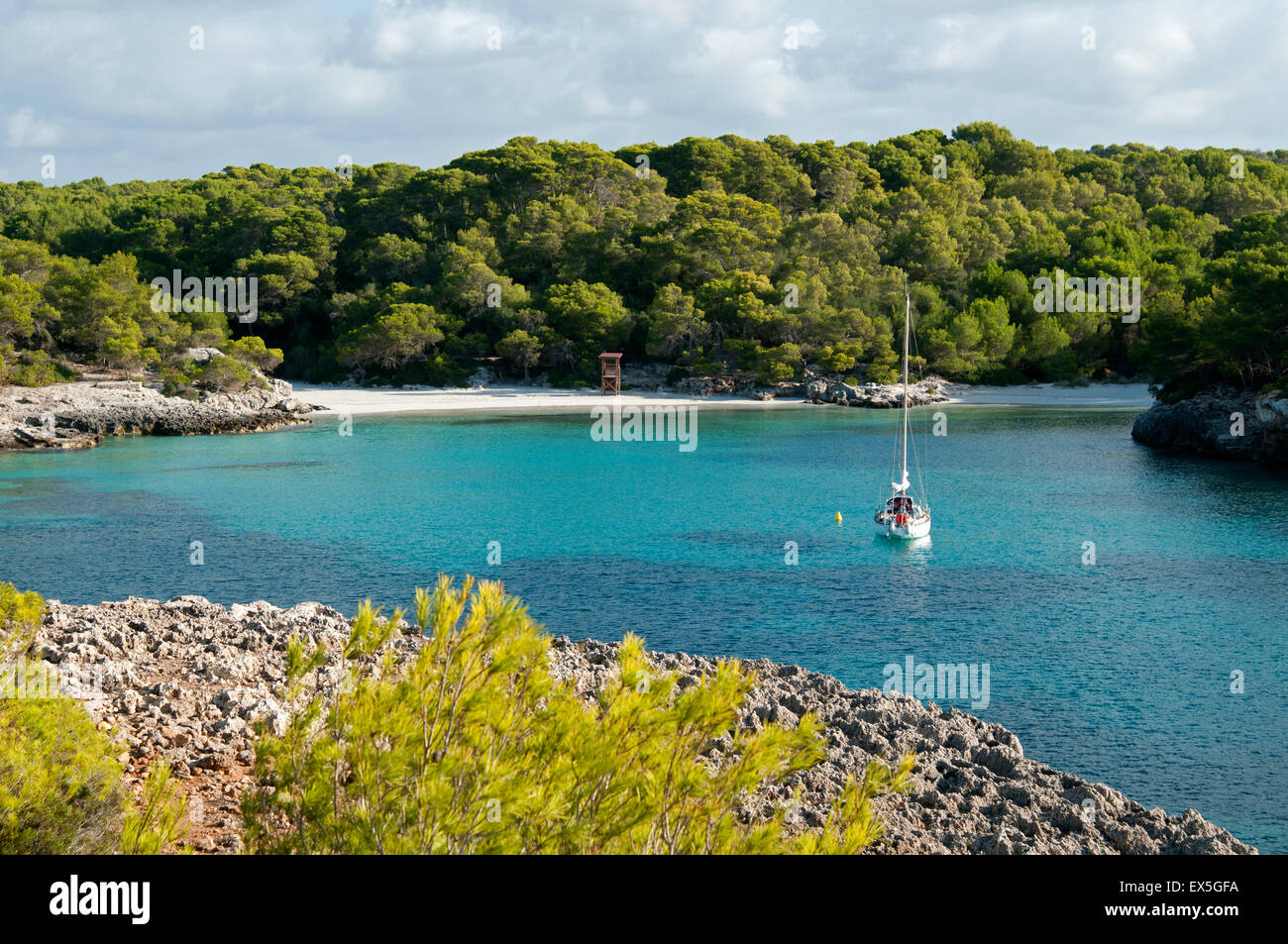 A sailing yacht moored in the calm turquoise waters at Cala Turqueta on ...