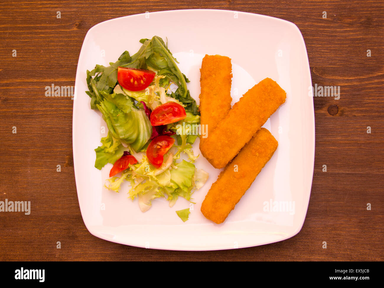 Fish fingers with salad on wooden table seen from above Stock Photo - Alamy