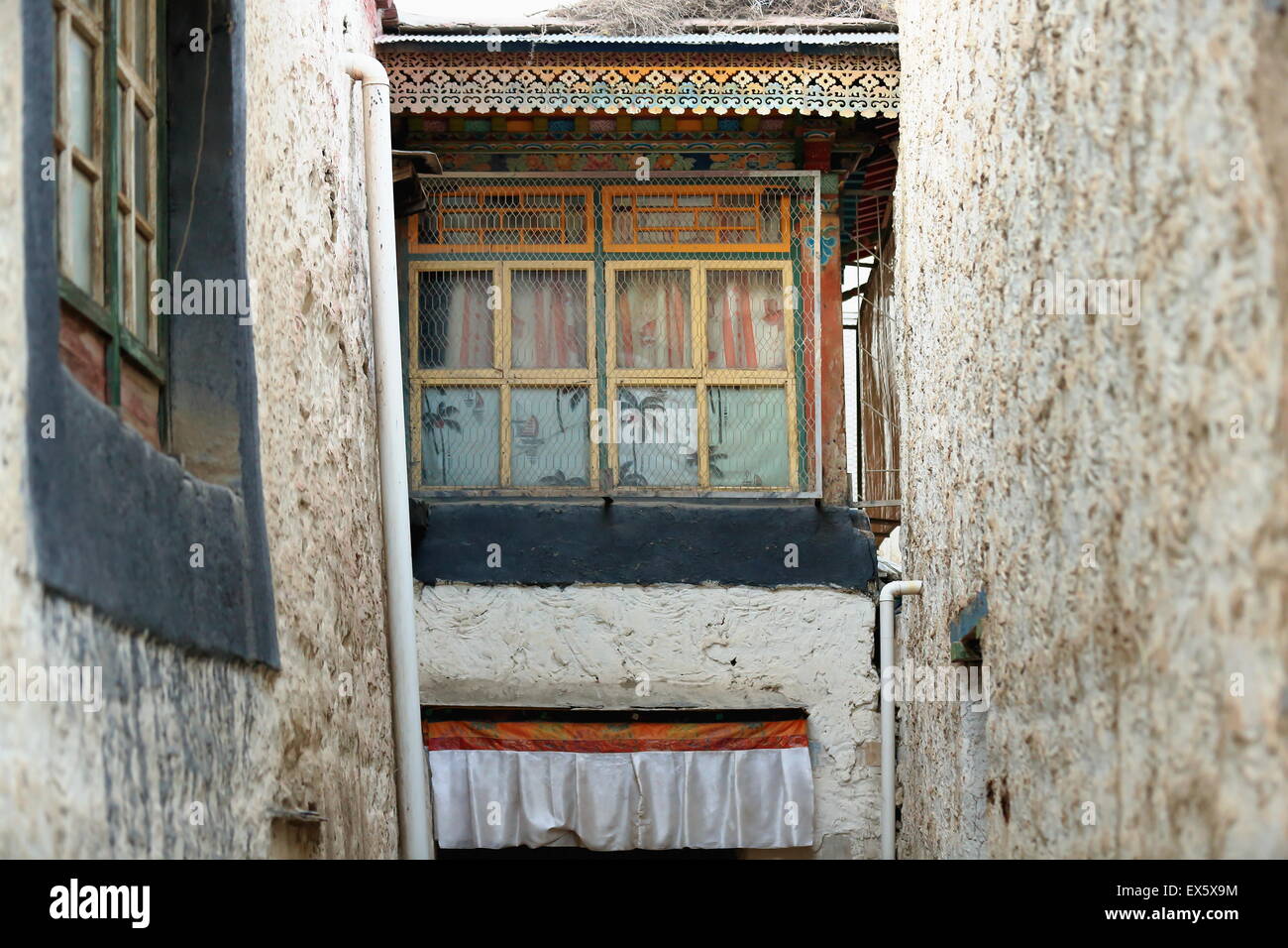 Manycolored carved roof eaves over wooden window with fabric curtains ...