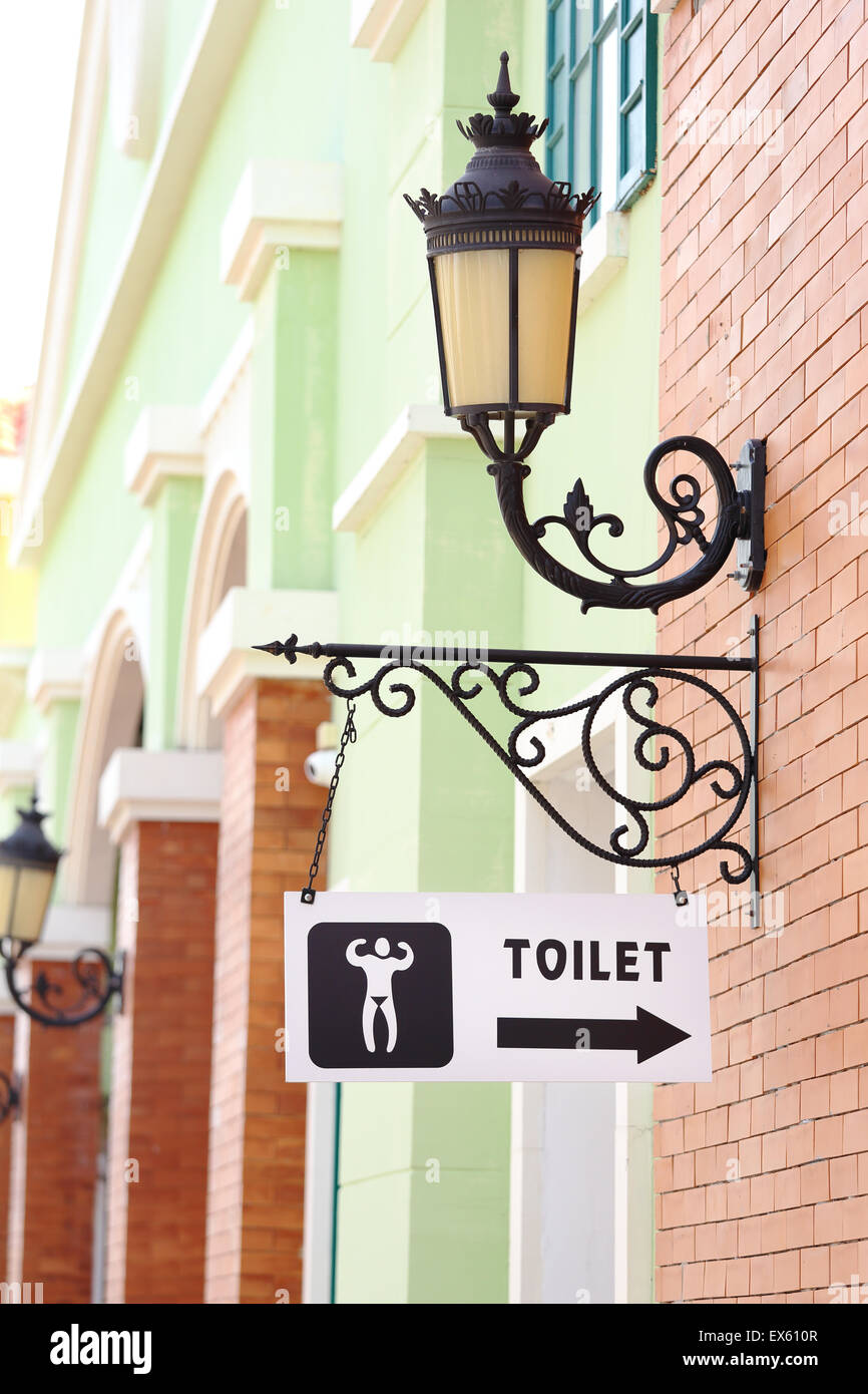 toilet sign hanging on brick wall and vintage lamp Stock Photo - Alamy