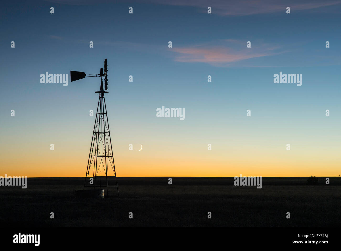 rural landscape with windmill in eastern Colorado at sunset with moon ...