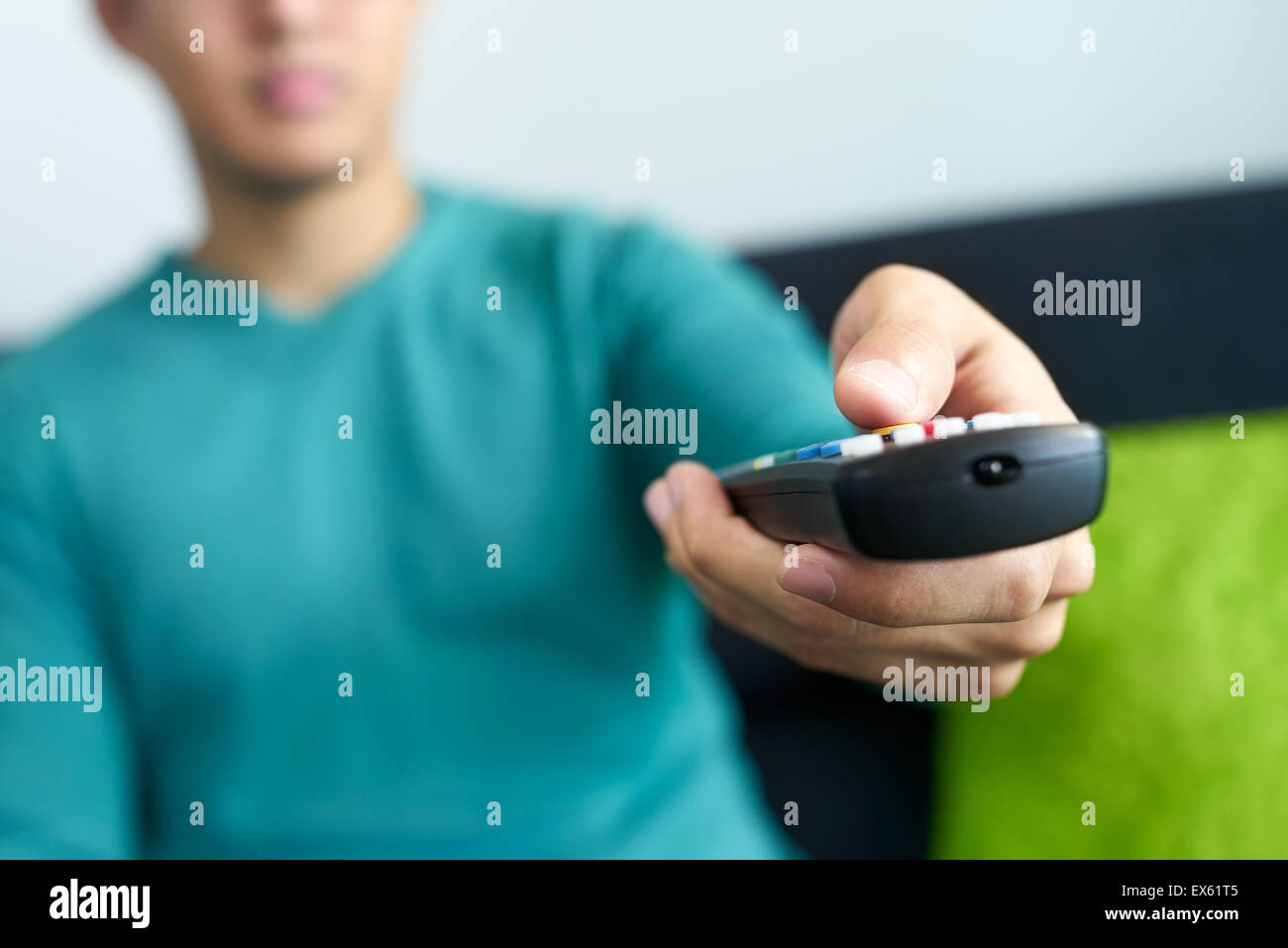 Asian young adult man watching TV and changing channel with remote ...