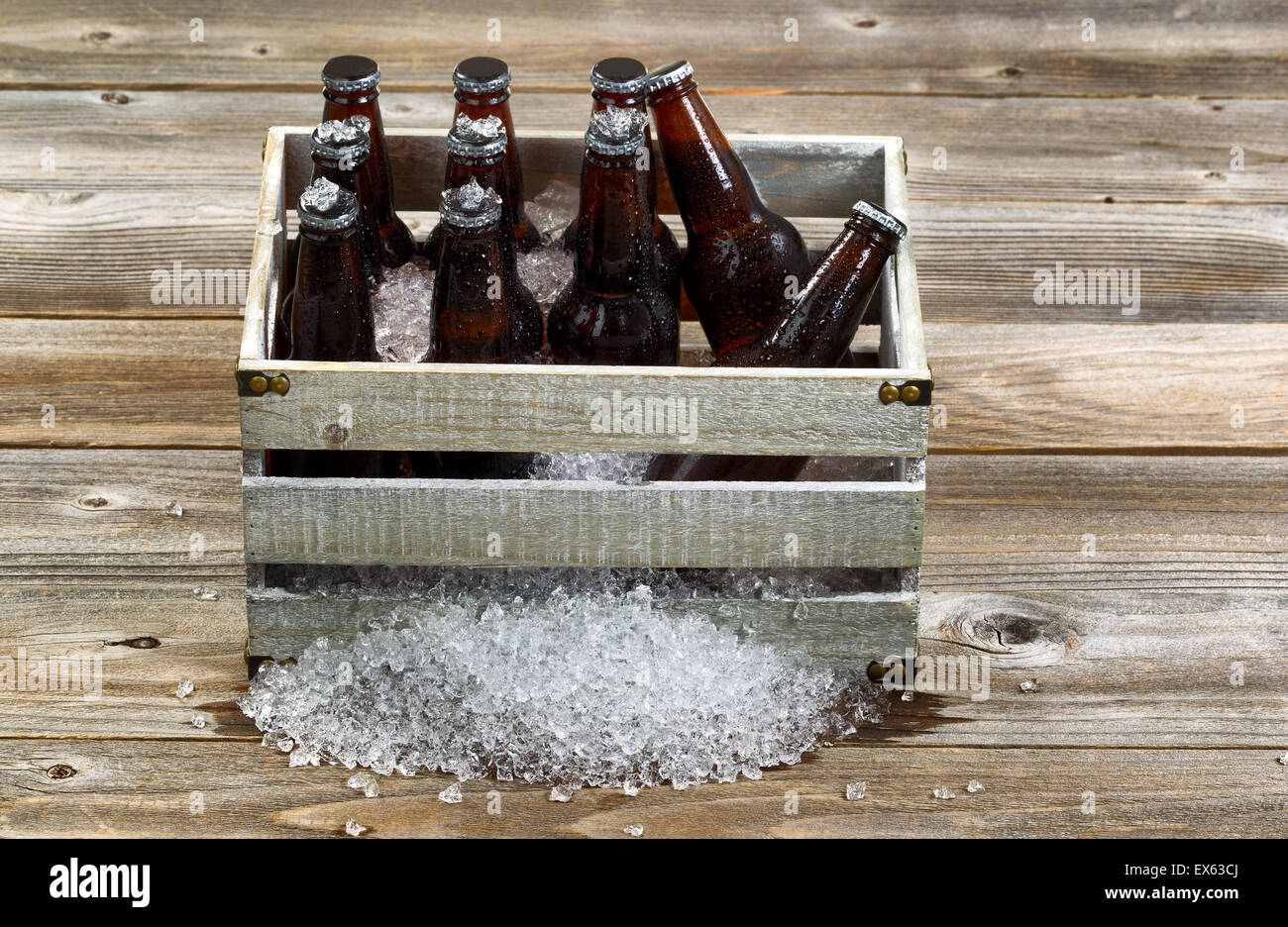 Vintage crate filled with bottled beer and crushed ice on rustic wooden ...