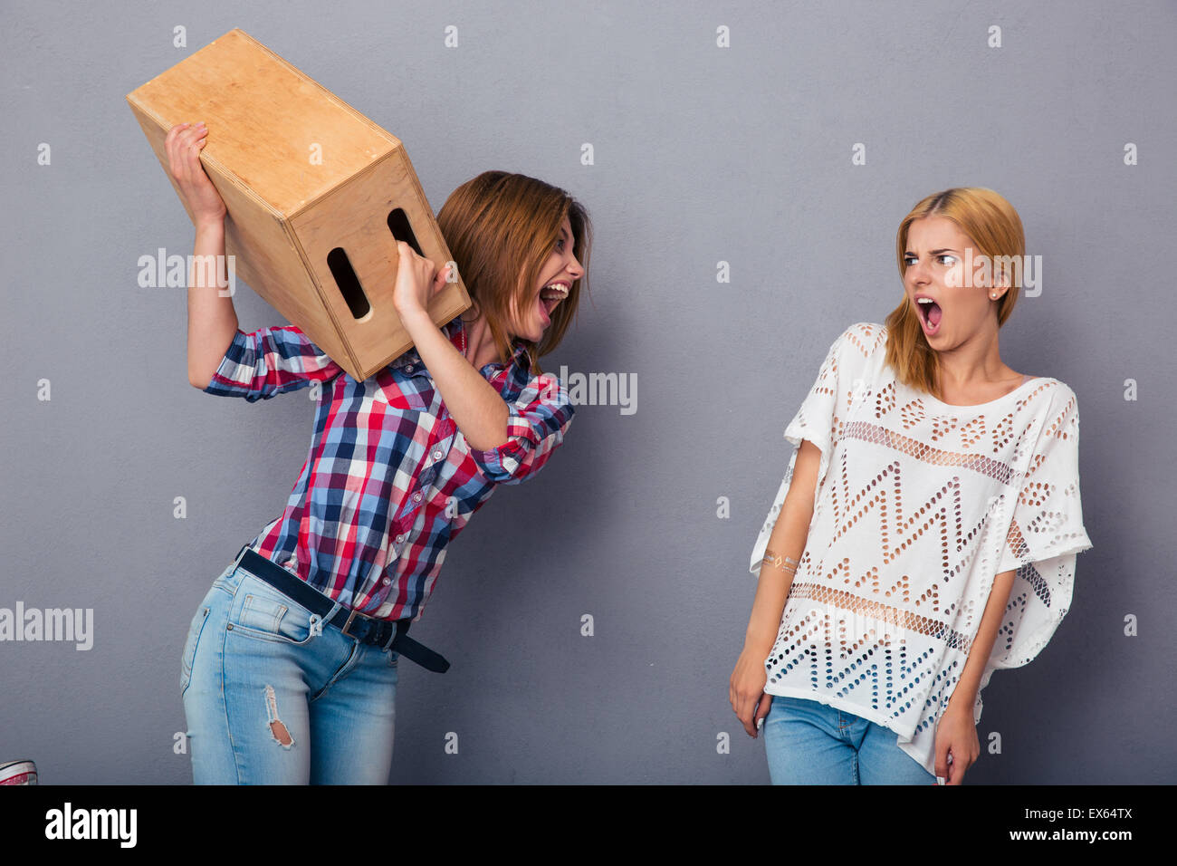 Two women quarrel over gray background Stock Photo - Alamy