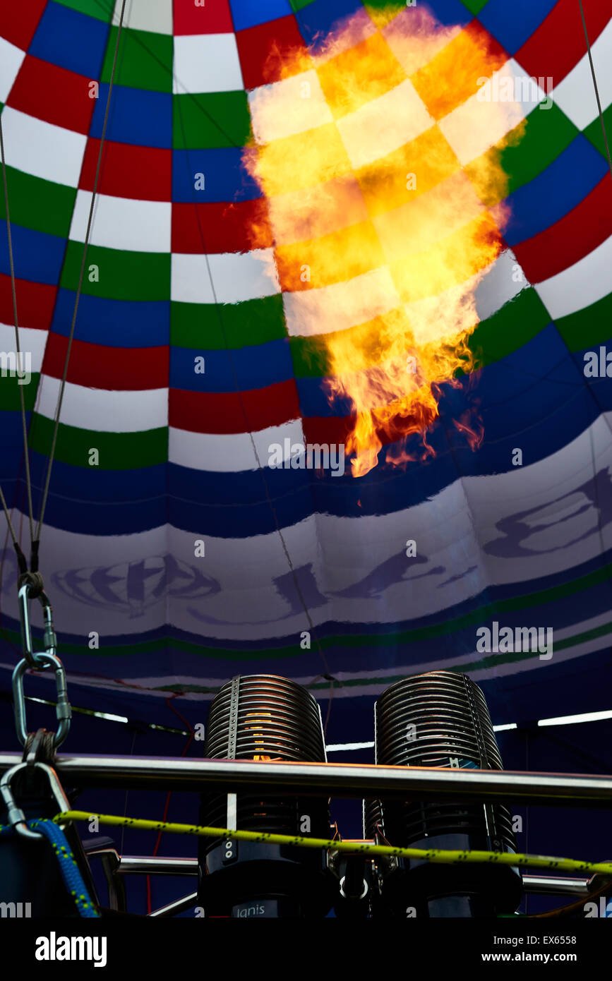 A burner with its super hot flame light up the inside of a colorful hot ...