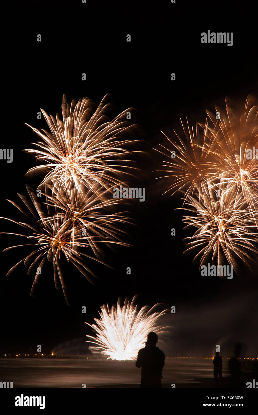 People admiring pyrotechnic show from the beach fireworks reflecting in ...