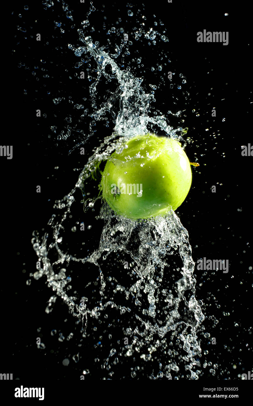 Green apple with water splash on black background Stock Photo - Alamy